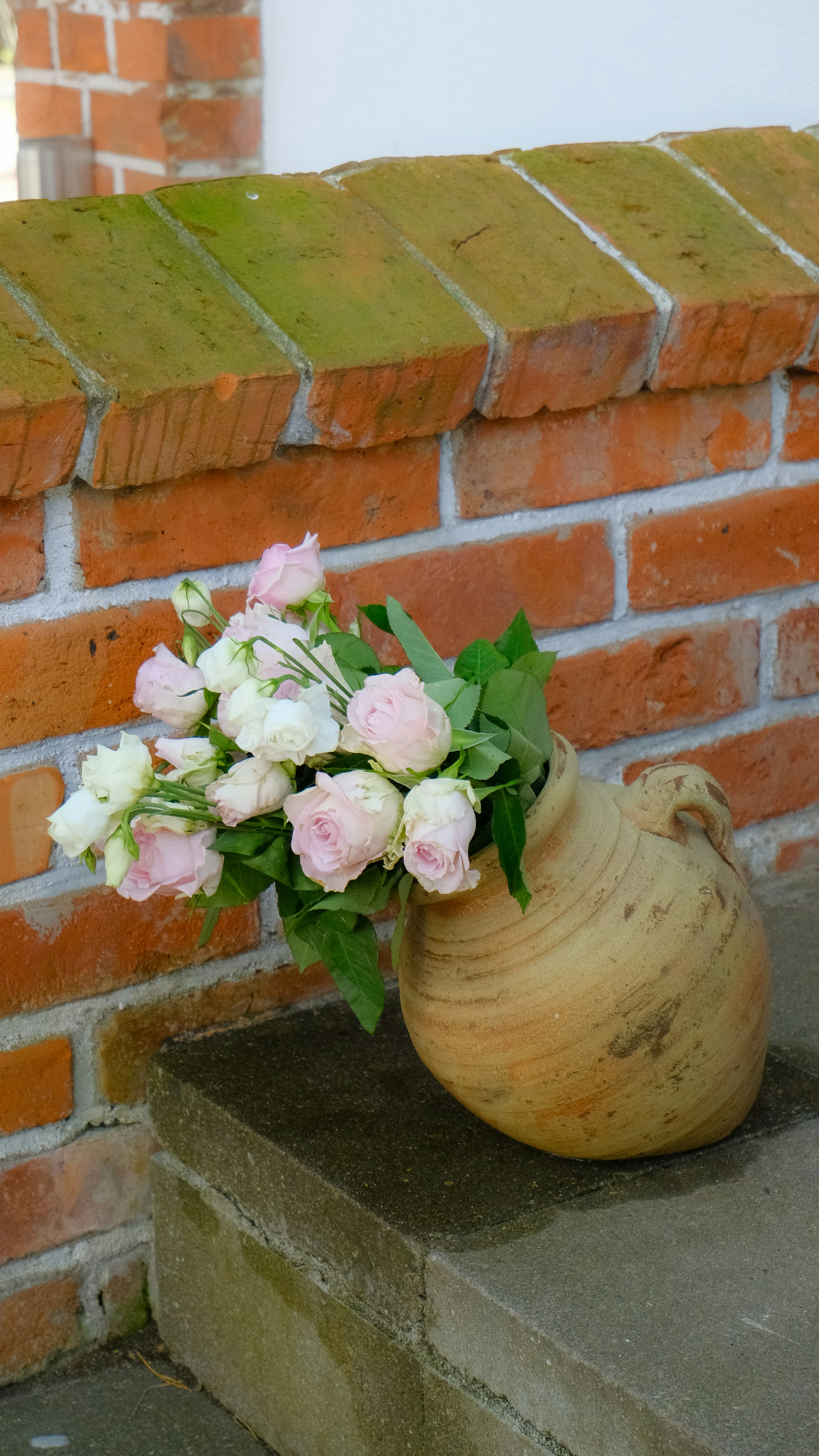 Rose Bouquet in a Rustic Pitcher Against a Brick Wall