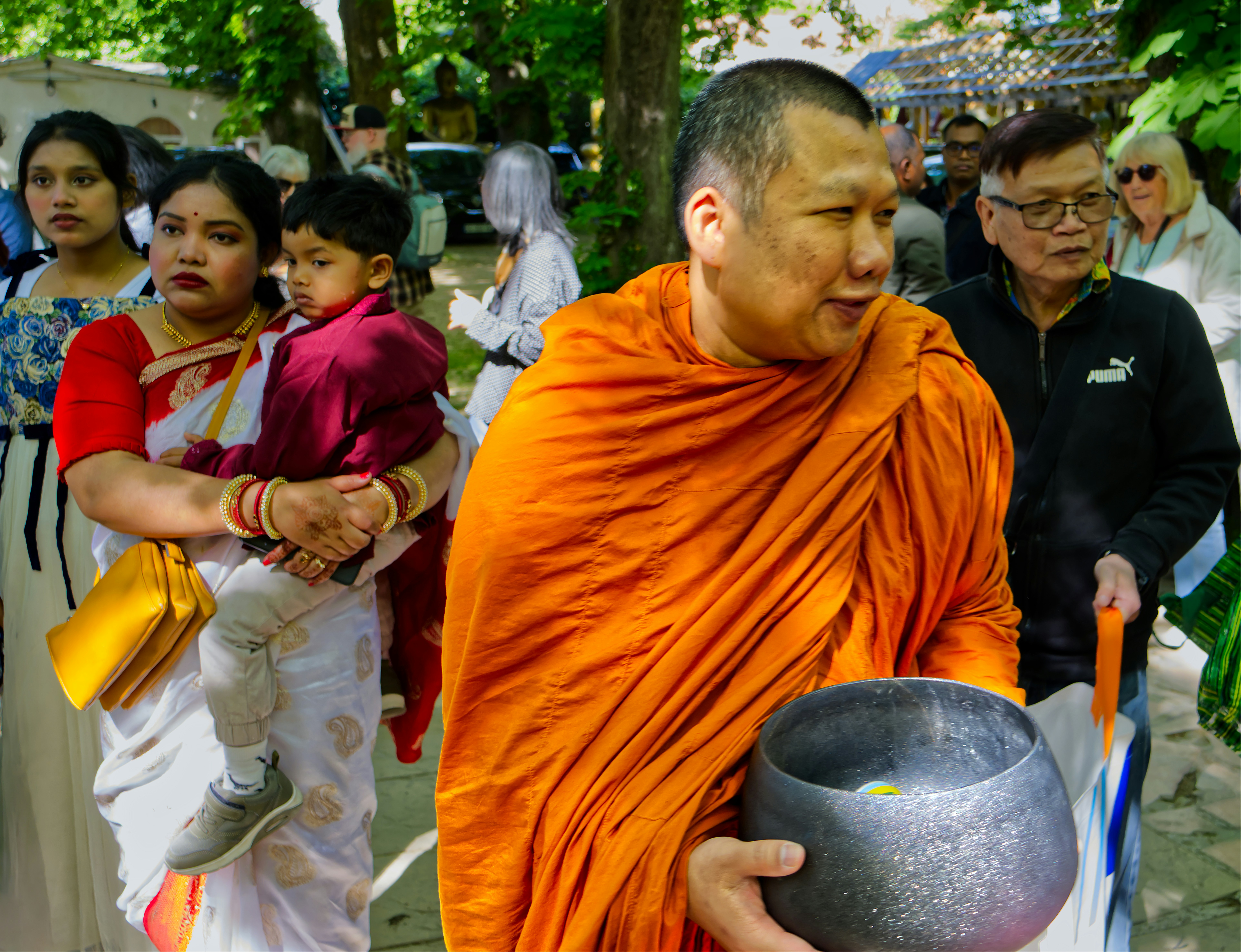 Monk in Orange Robe Among Curious Crowd at a Cultural Gathering