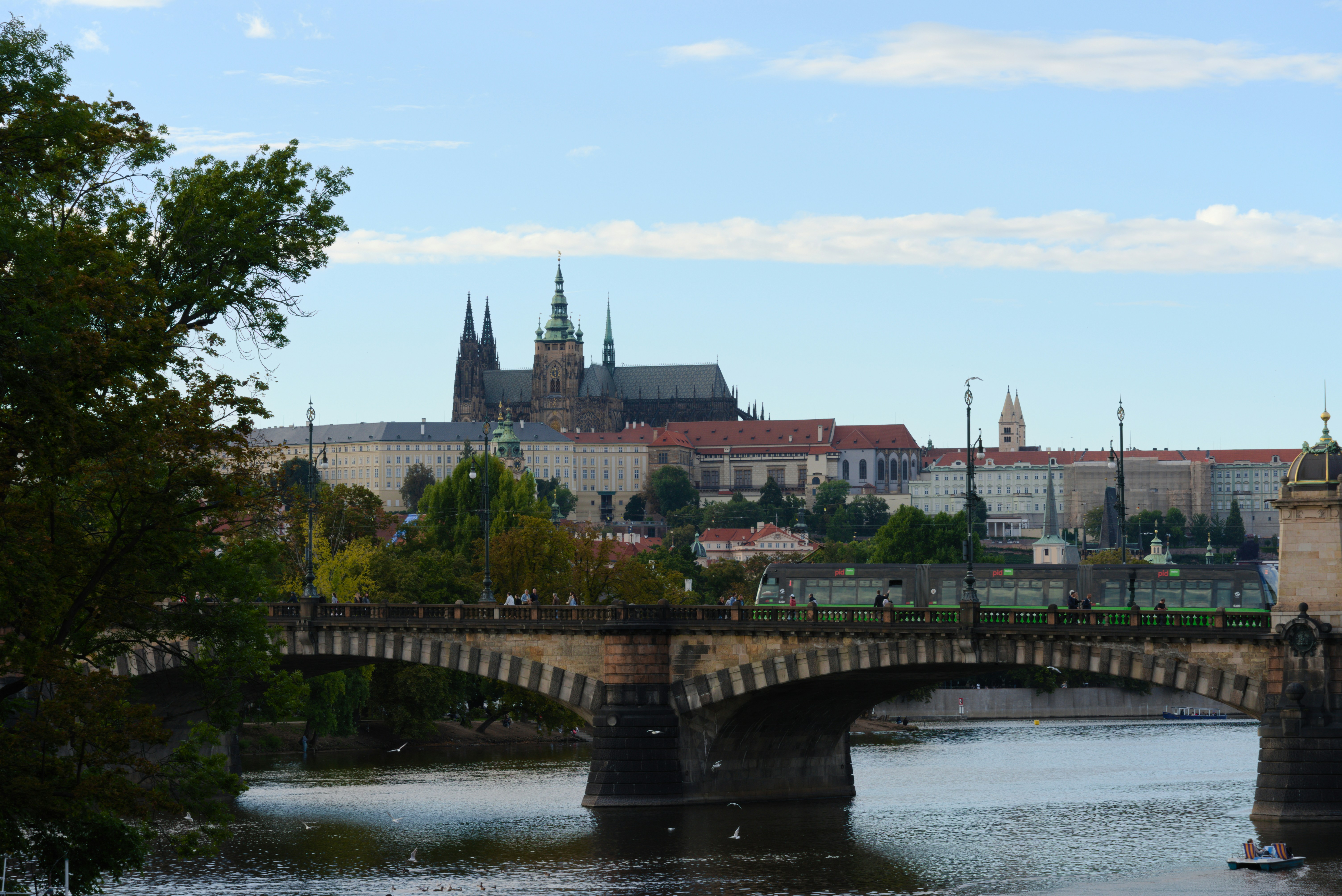 Brick-arched bridge over the Vltava with Prague Castle silhouetted at dusk