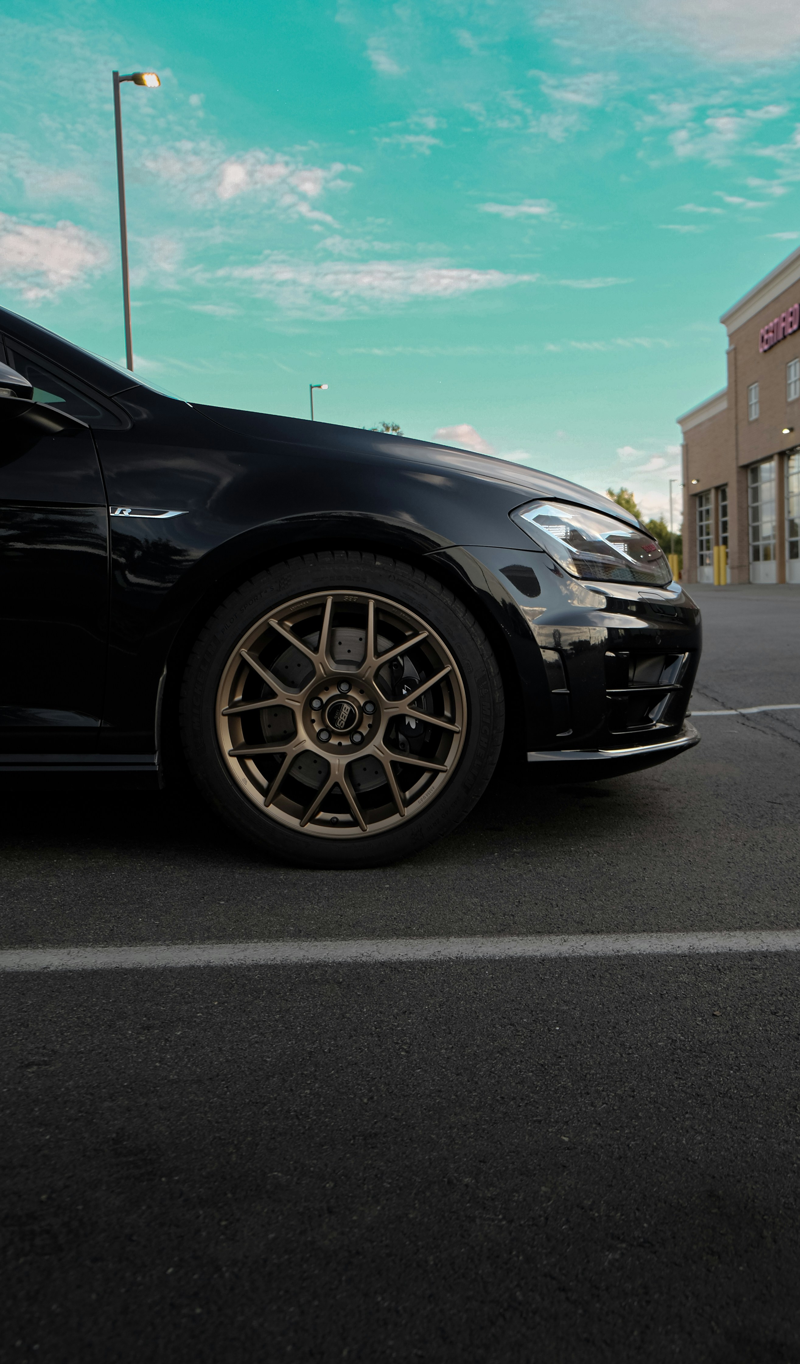 Low-angle glimpse of a tuned black sedan in a sunlit lot