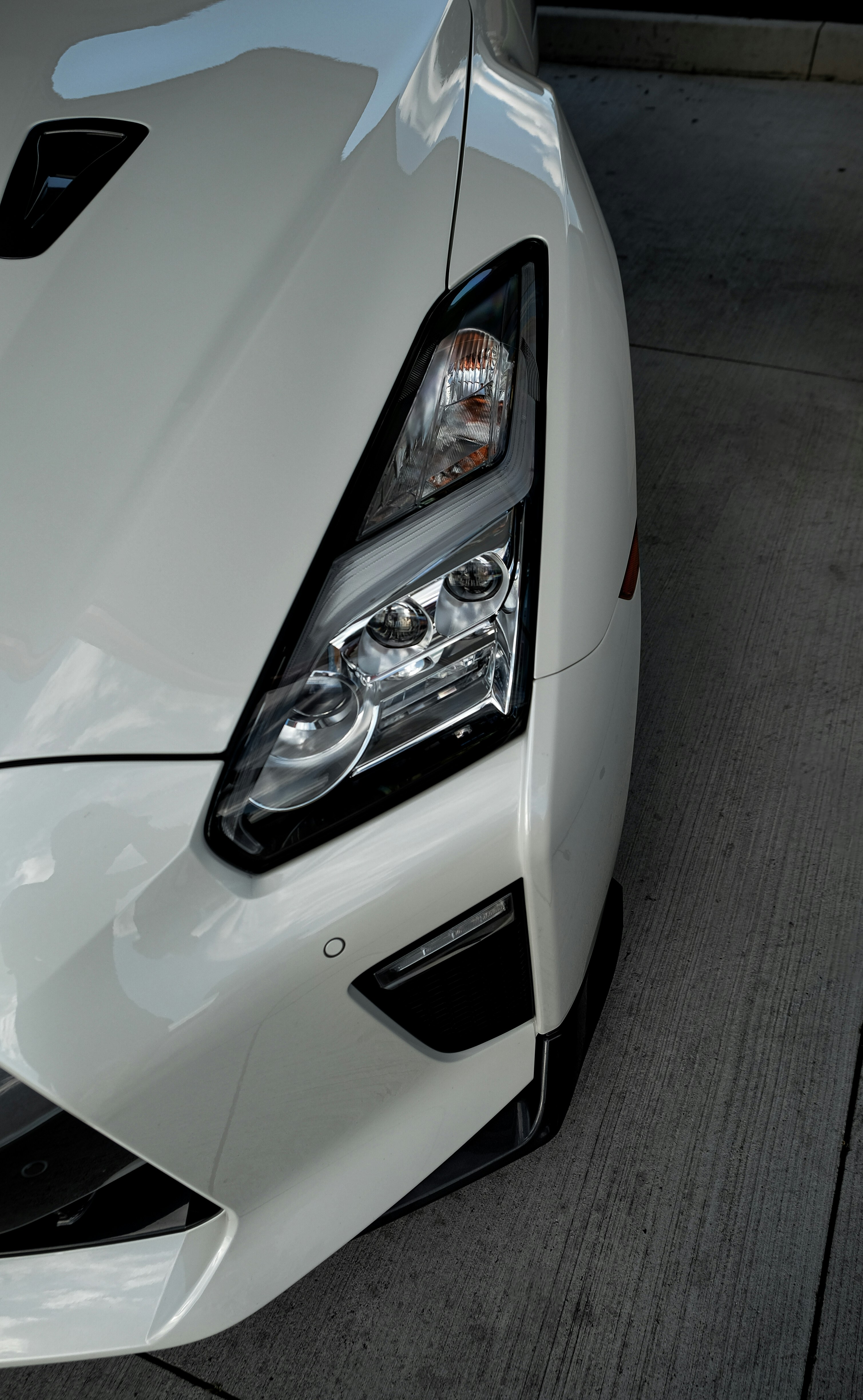 Close-up of a silver sports sedan’s headlight and front bumper edge