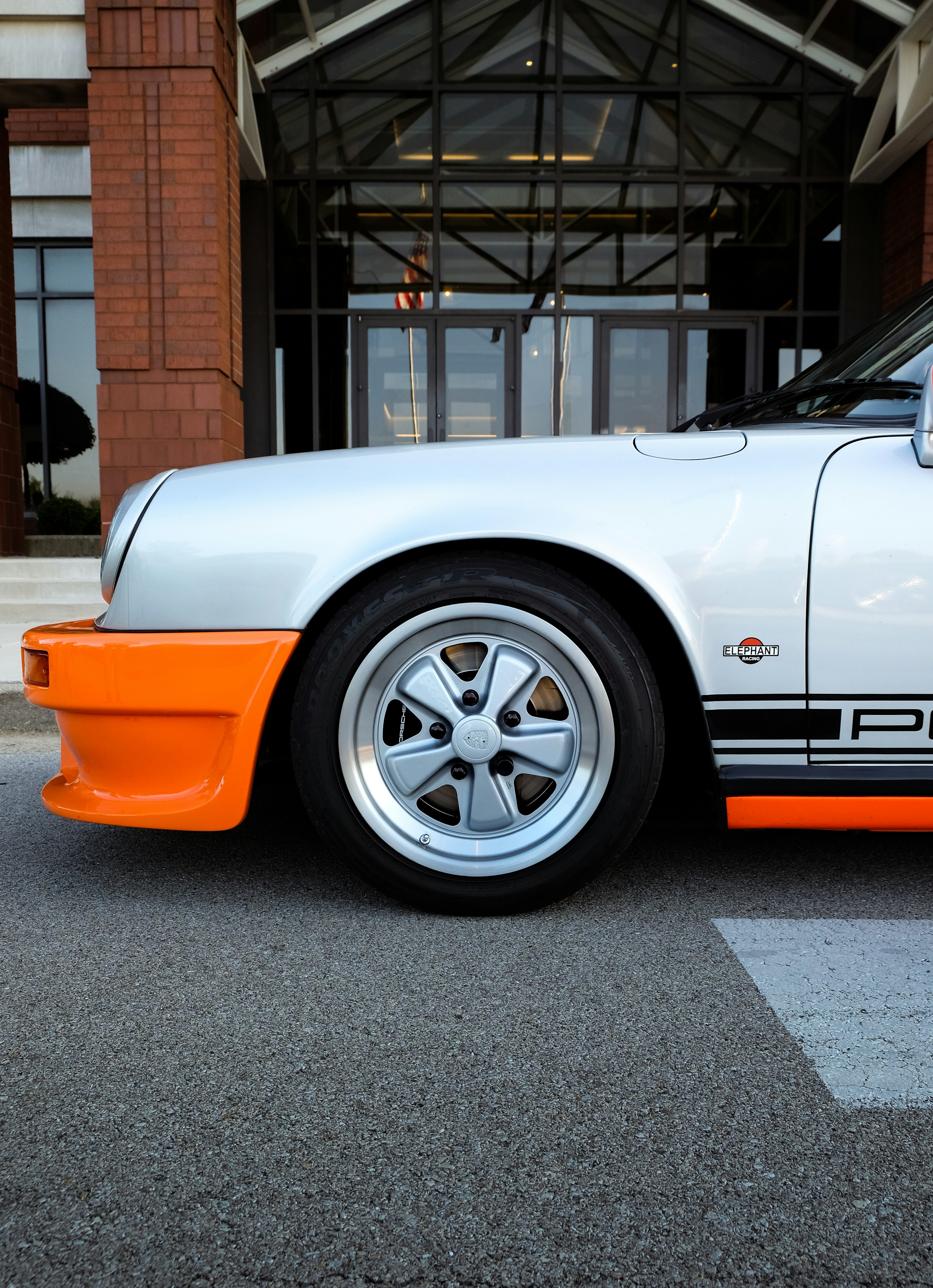 Orange-Bodied Stance: A Classic Front-Quarter of a White and Orange Porsche-styled Car