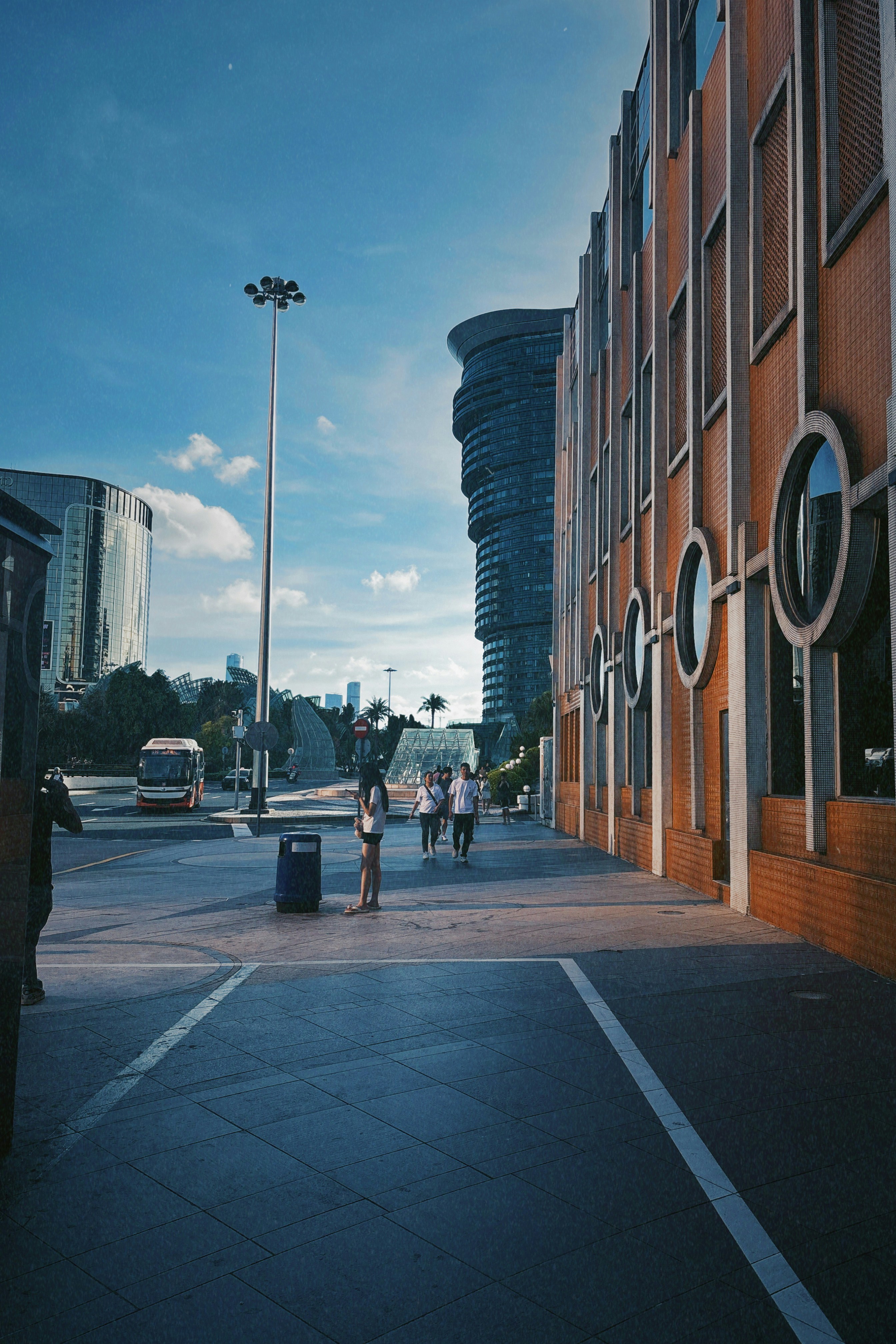 Urban Channel: People Walk the Bright Boulevard By the Brick-Columned Wall