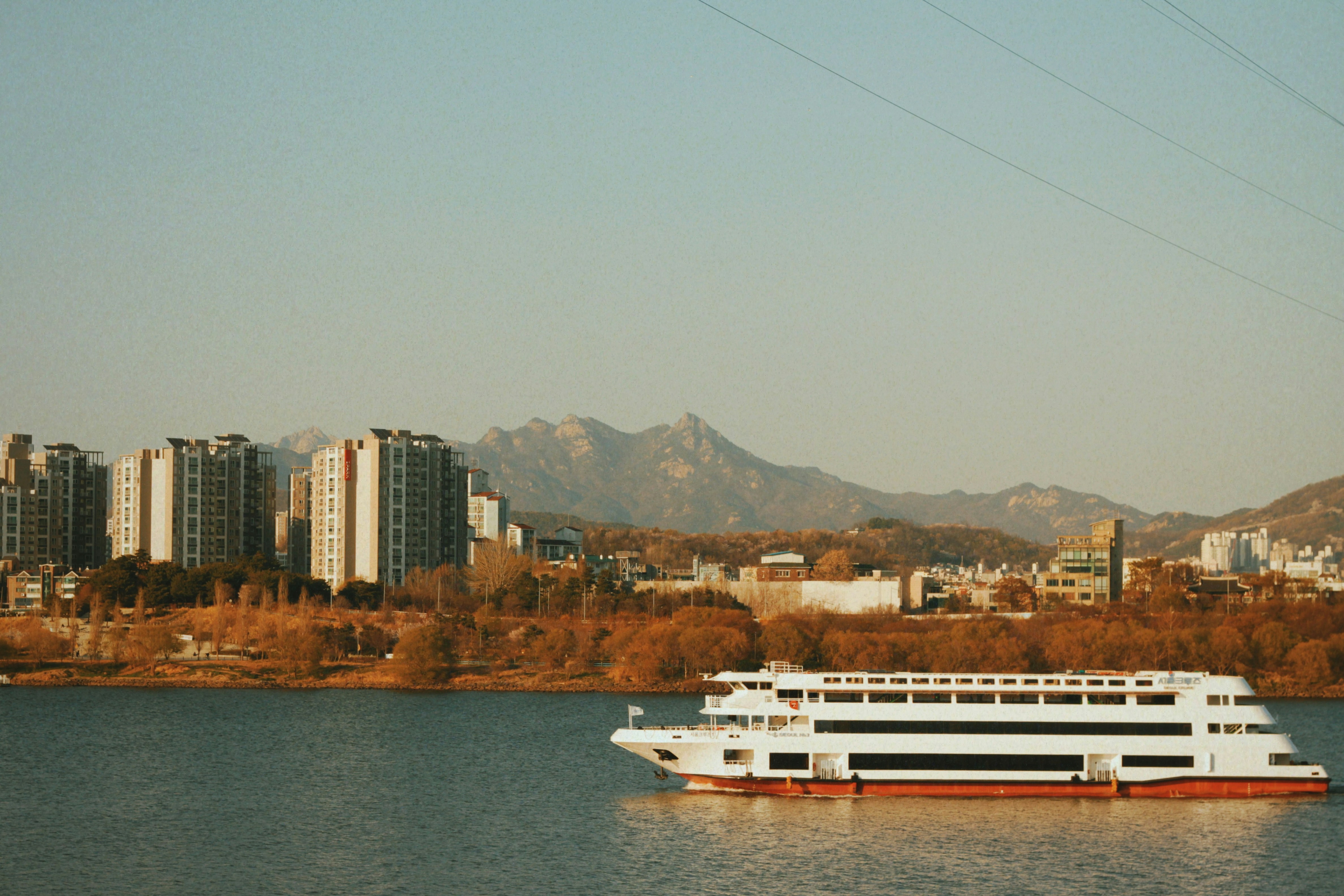 Riverfront Vessel at Dusk: A Cityscape and Mountain Backdrop