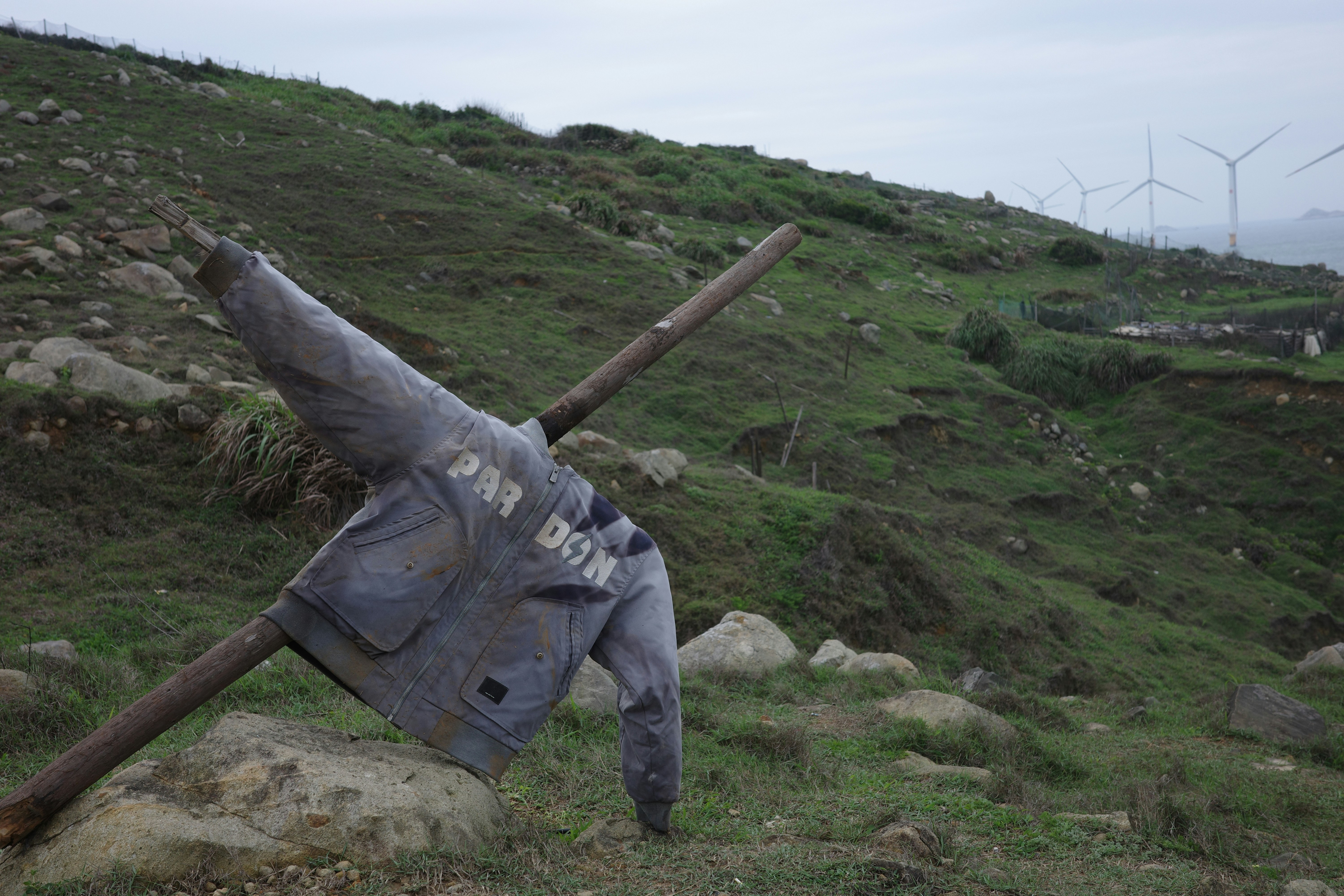 A worn jacket stands alone in a windswept field by the sea, like a forgotten trace of the cursed prince in Howl’s Moving Castle, as if something once human had quietly slipped out of its spell. It feels magical, yet strangely unsettling, suspended between memory, transformation, and myth.