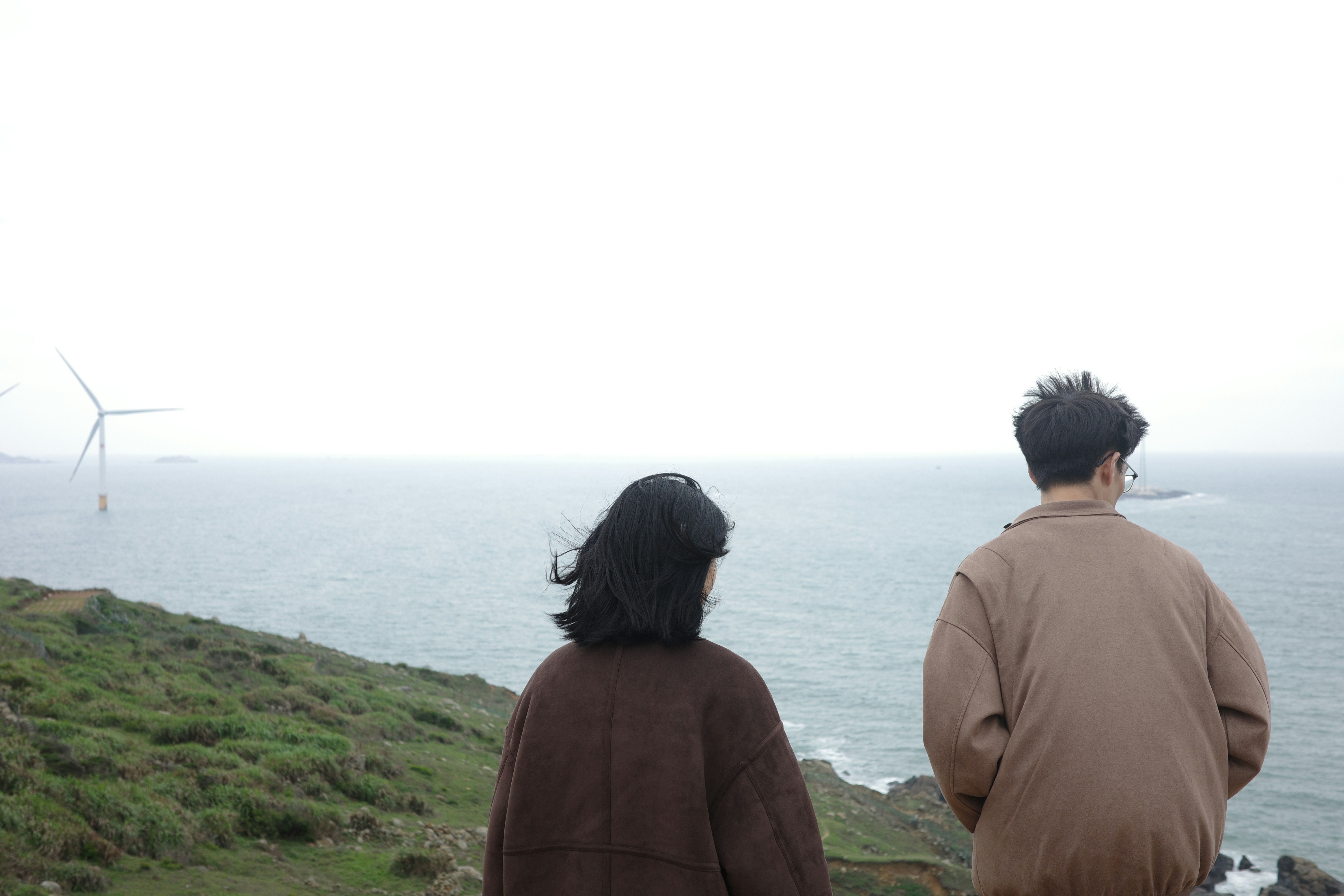 Coastal Gaze: Two silhouettes at the edge of the wind-swept cliffs