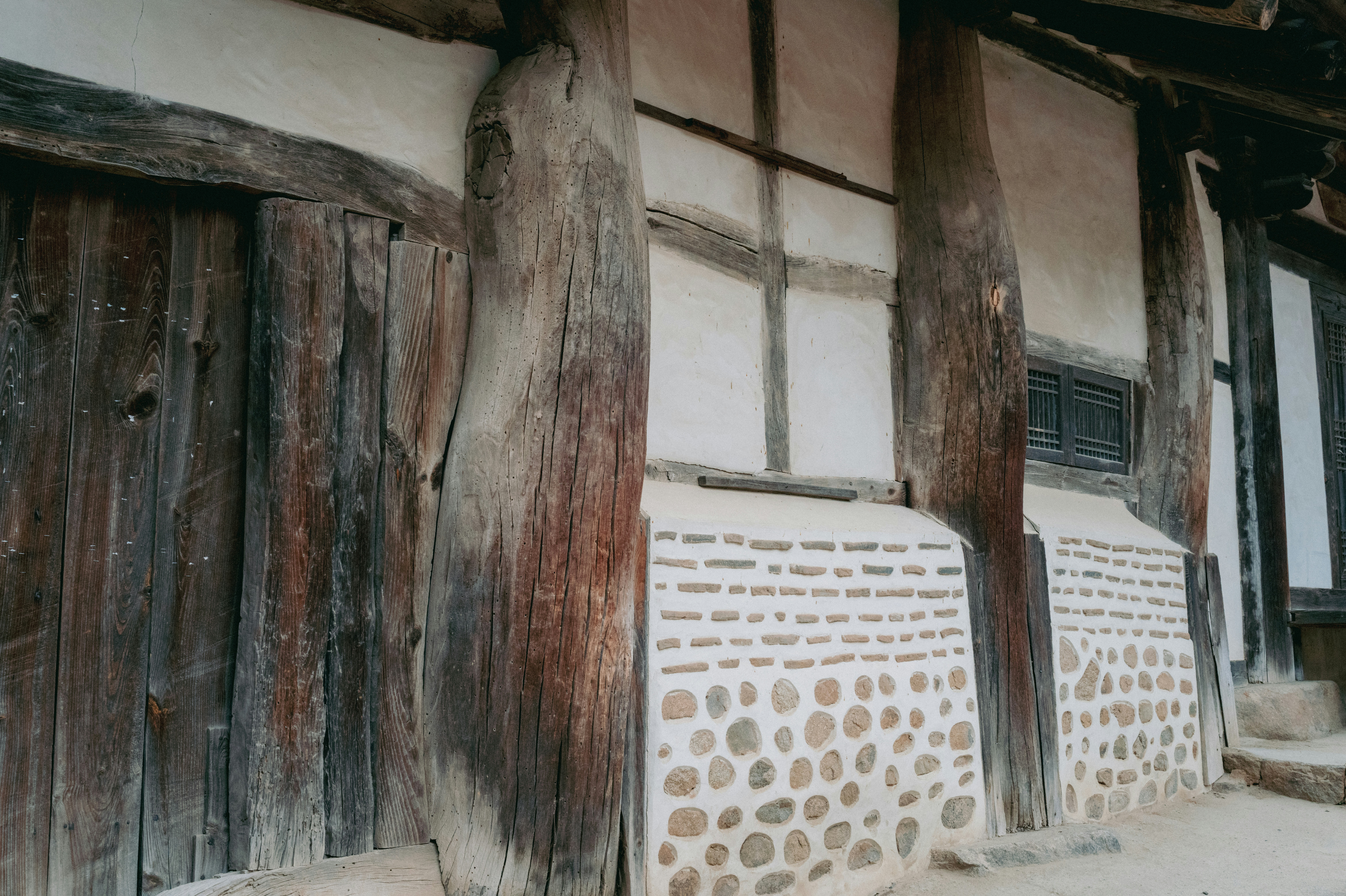 Weathered Wooden Facade: Stone Stripe and Timber Columns