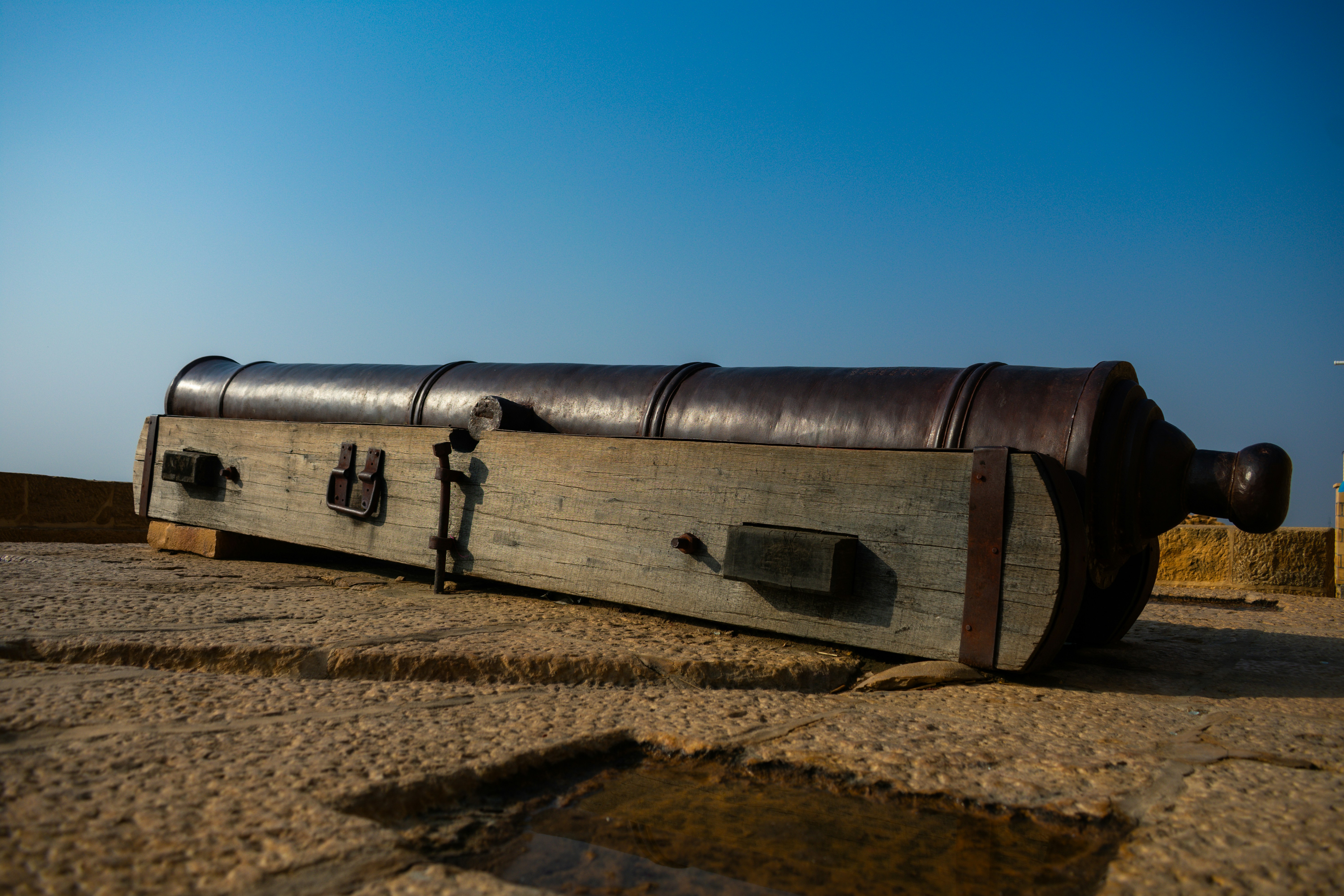 Weathered coastal cannon lying low on sunbaked stone