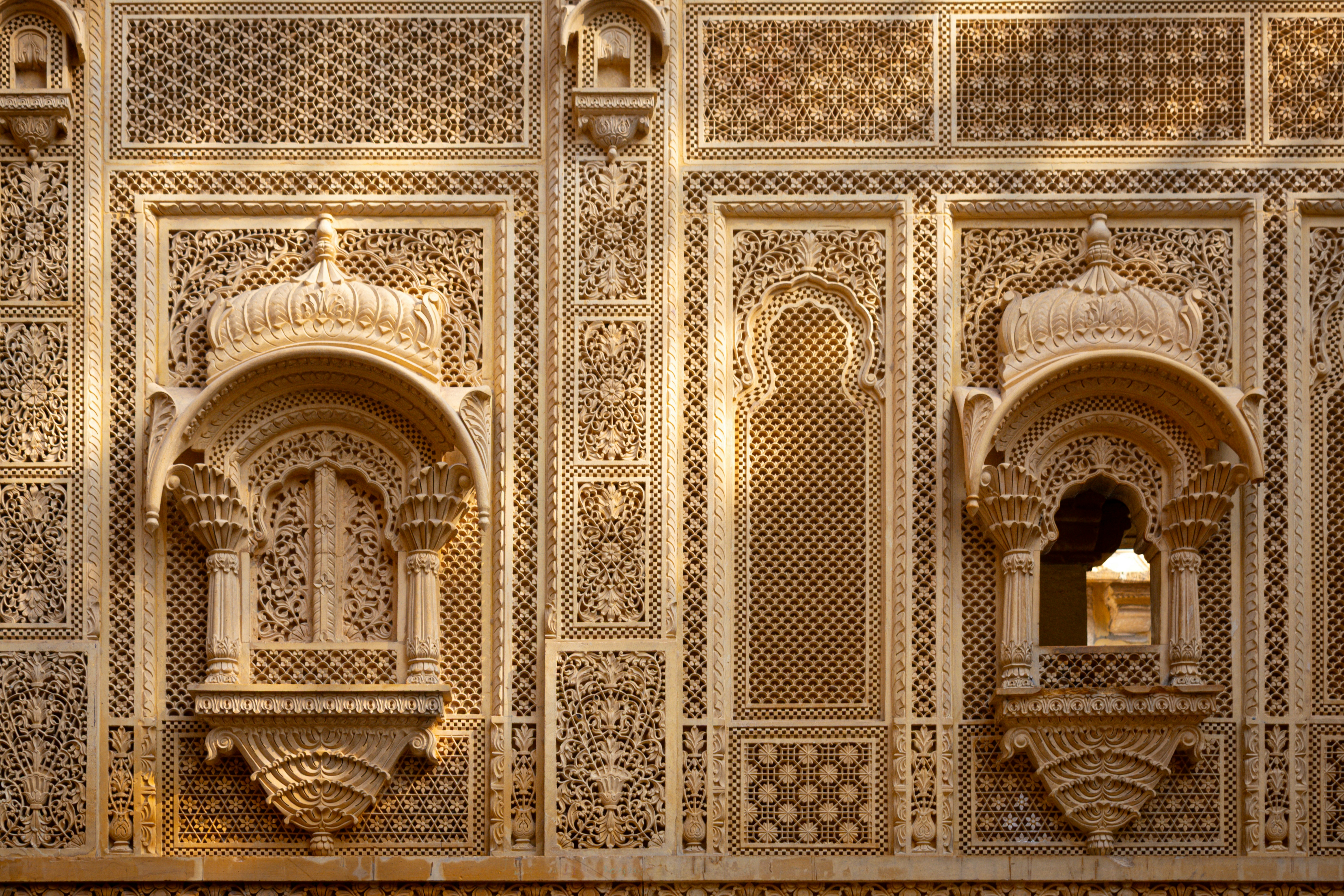Carved Pavilion Facade: Intricate Latticework and Excavated Niches on a Golden-Wedged Wall