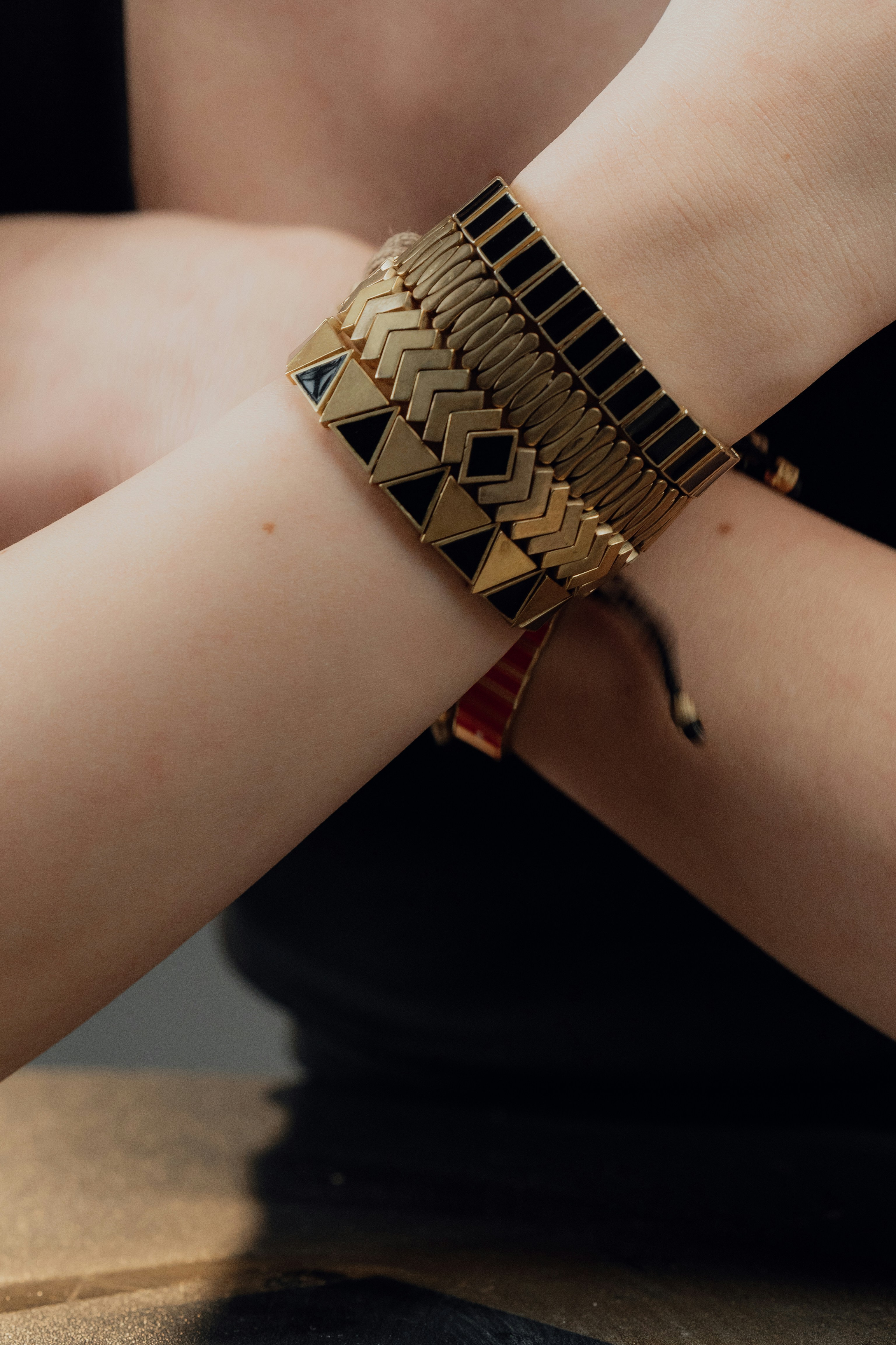 Brushed gold and onyx: stacked bracelets framing a poised forearm