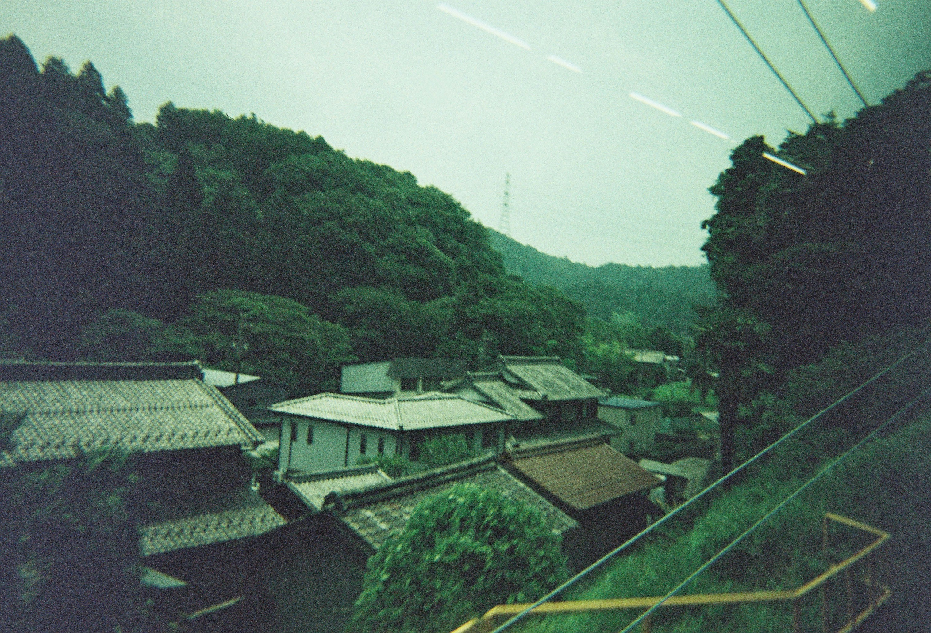 Train Window Overlook: Quiet hillside village under a teal sky