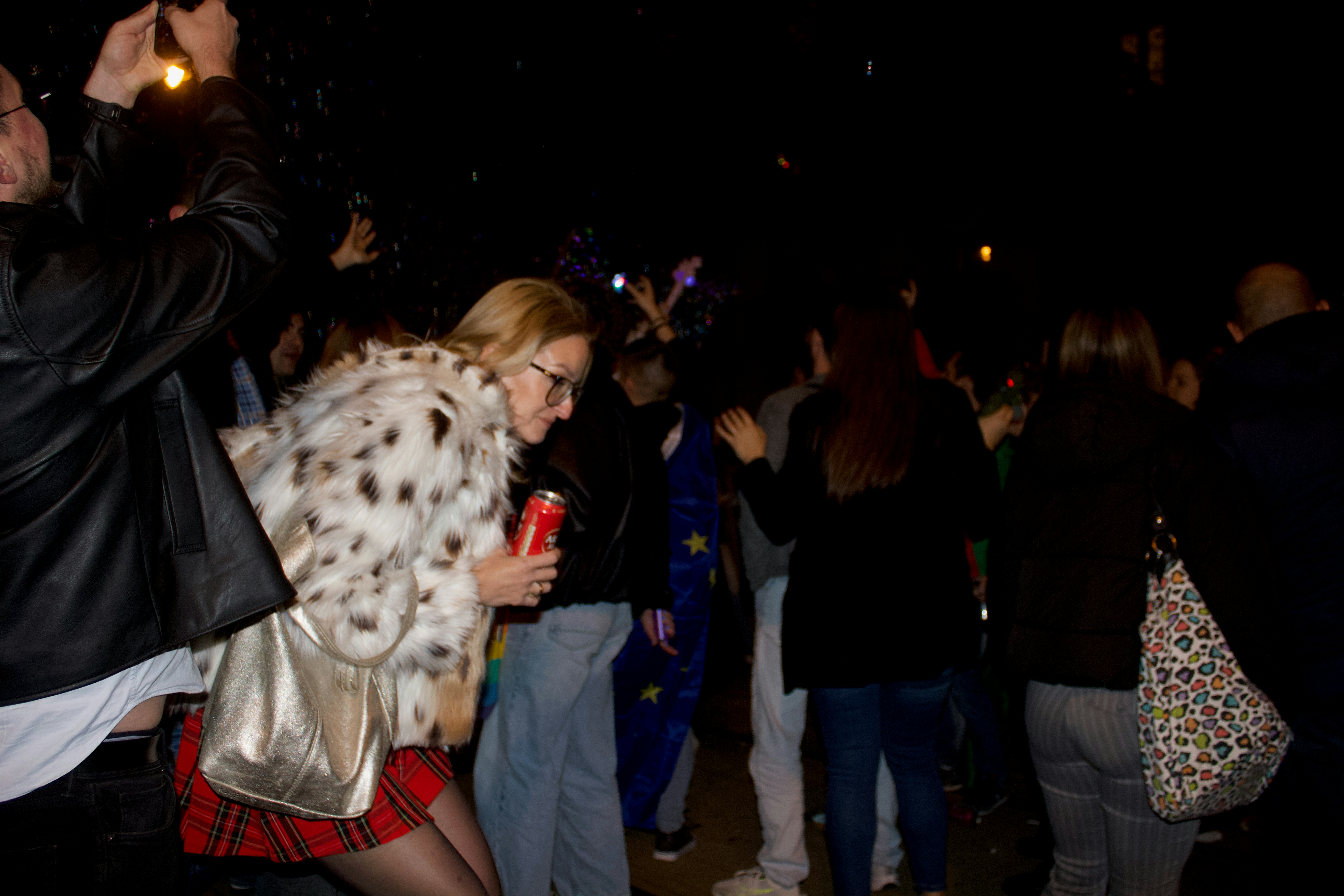 Midnight Crowd: A Woman in Faux Fur Reaches for a Red Can