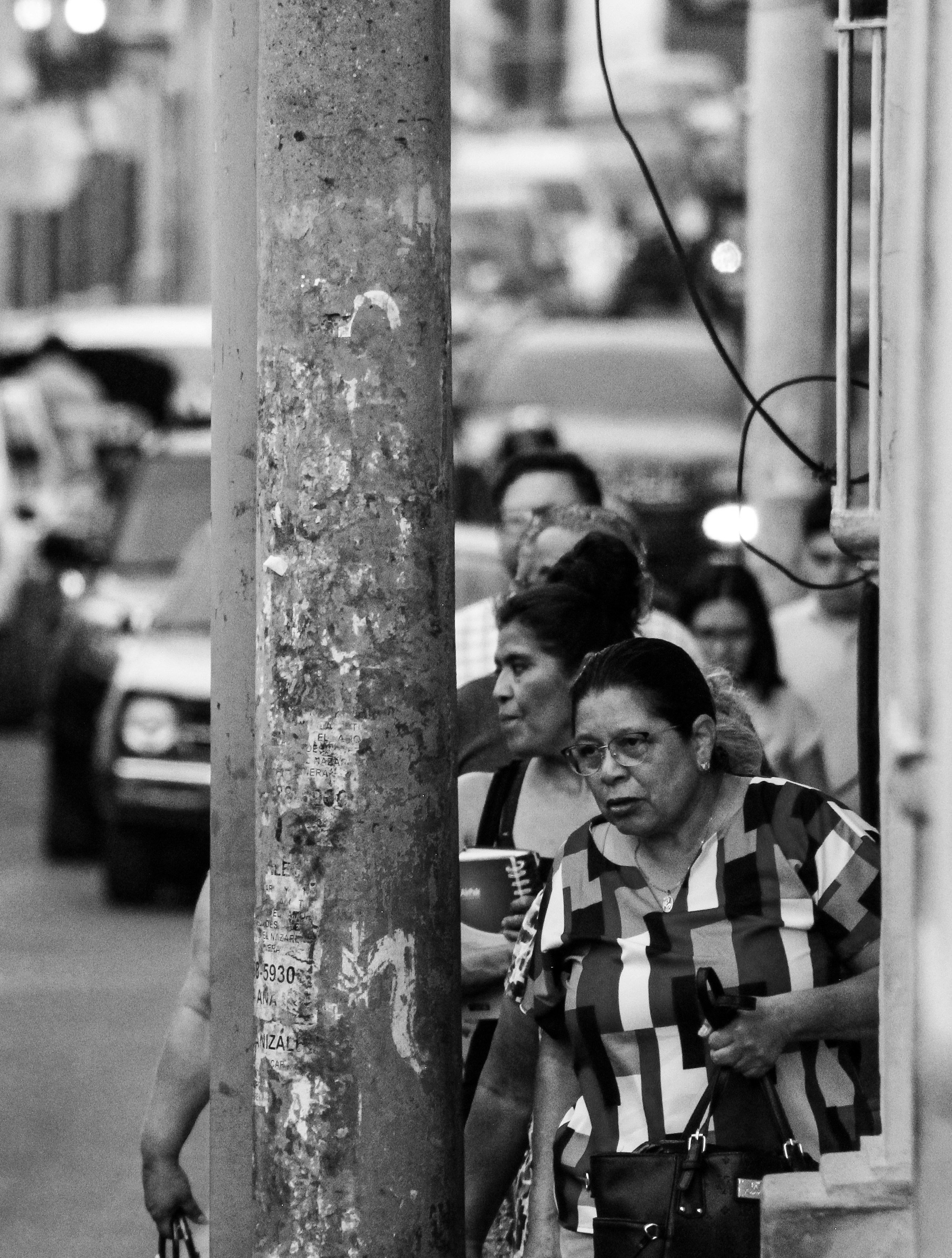Street Scene in Black and White: The Woman with Glasses by the Pole