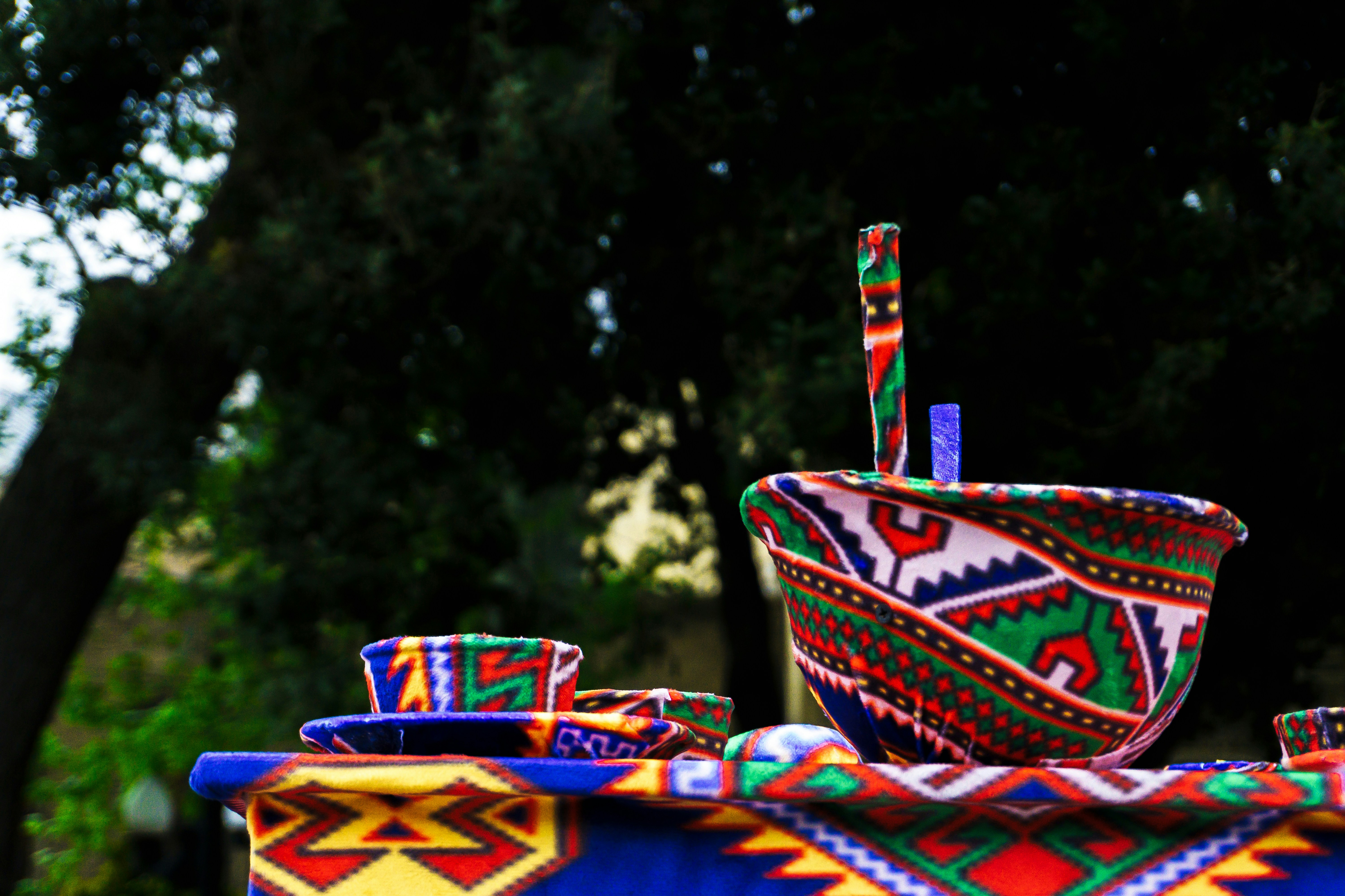 Colorful woven baskets spill over a vibrant textile setup in a sunlit outdoor scene