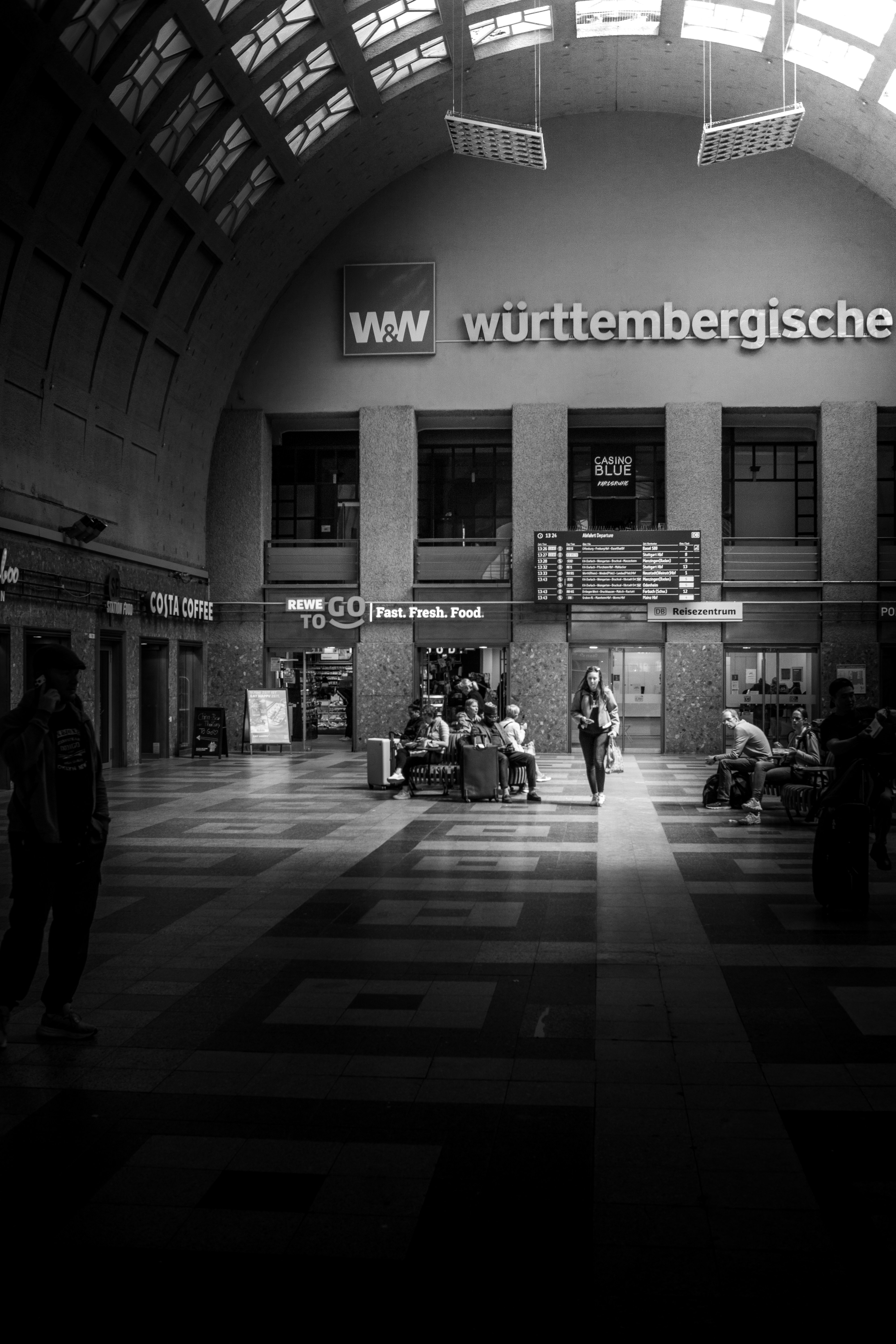 People Gather Under the Arched Station, Waiting for a Sign