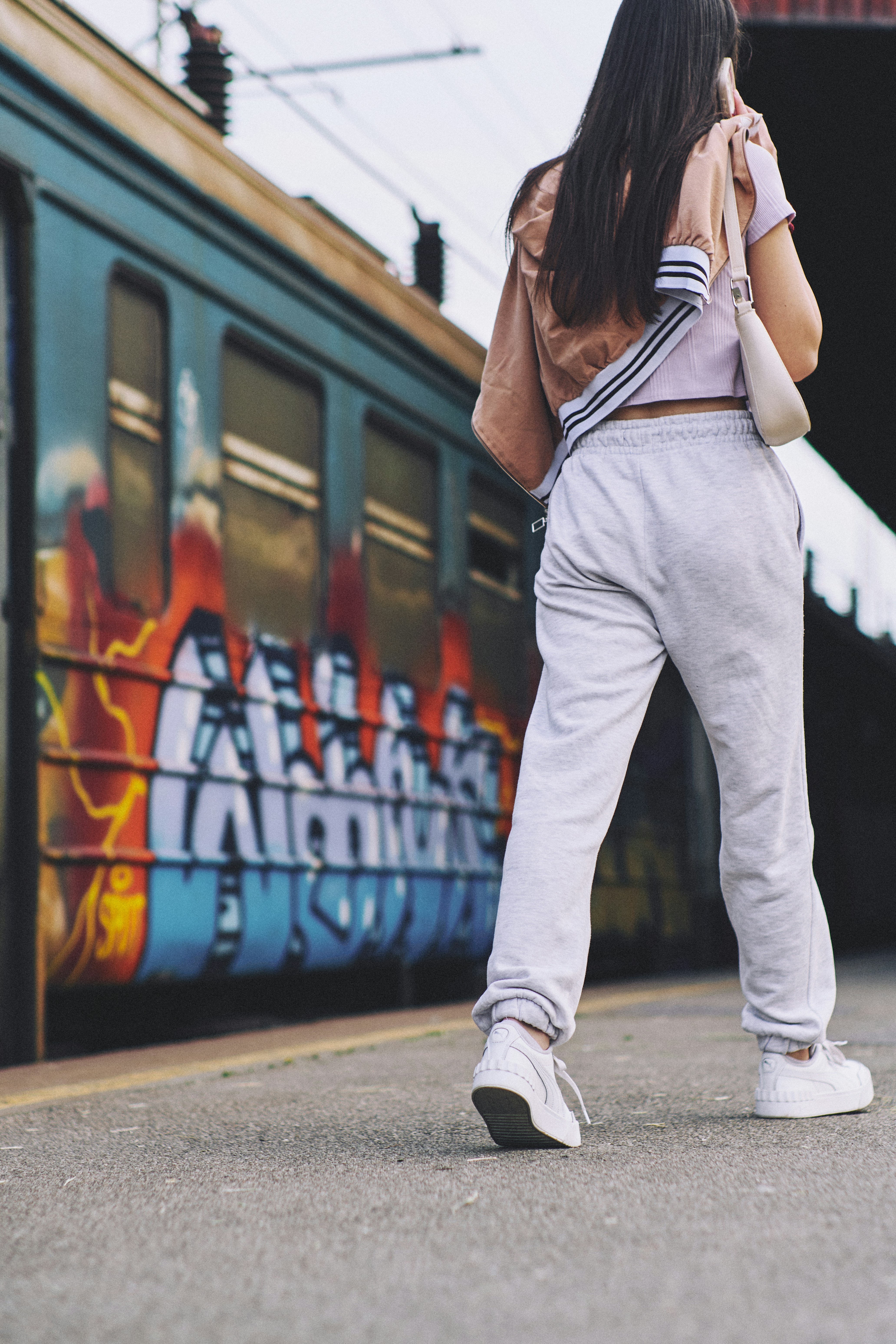 Backlit silhouette of a stylish traveler against graffiti-bathed train car