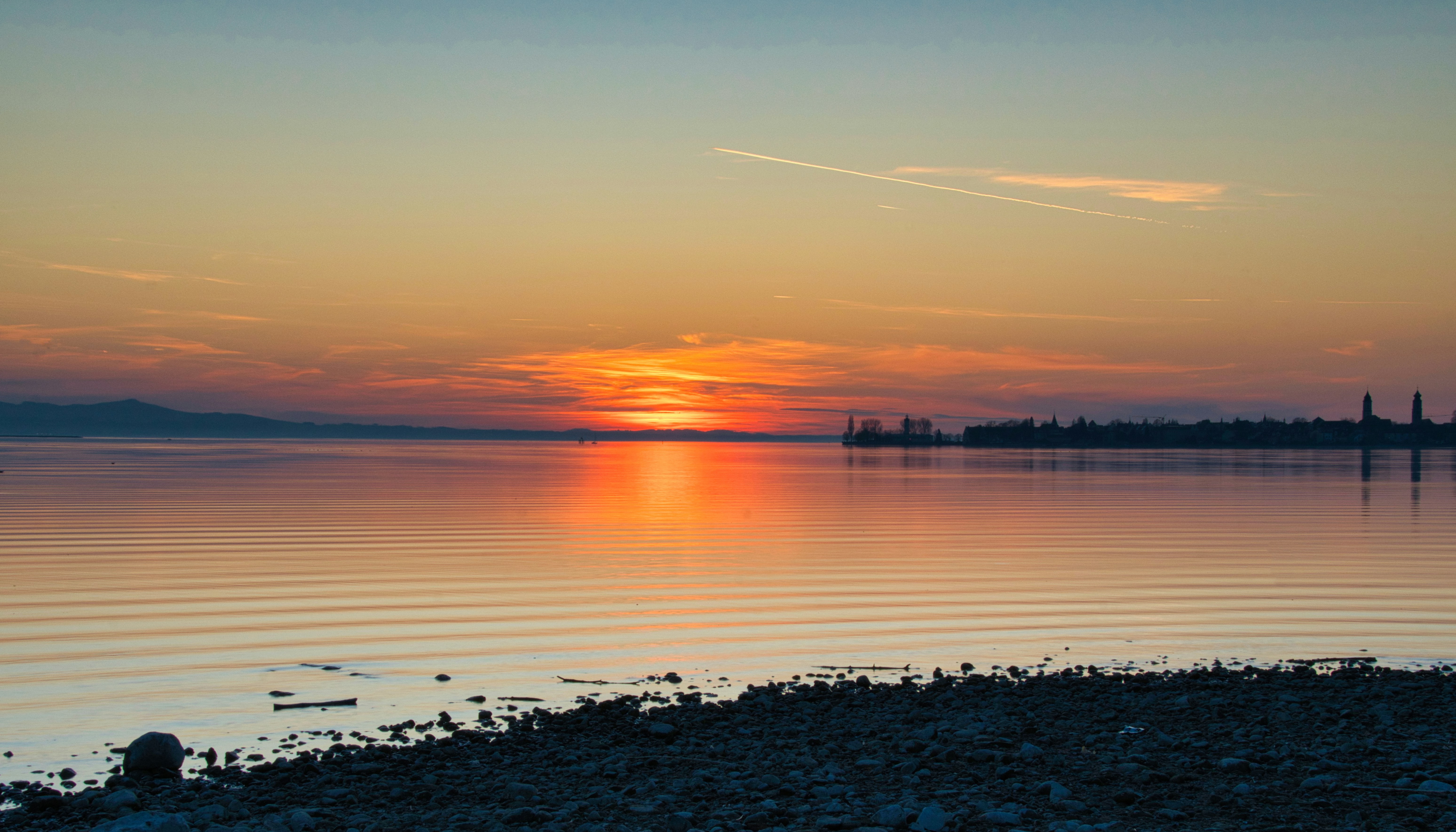 Dawn on Glassy Waters: A Quiet Horizon over a Pebble Shore