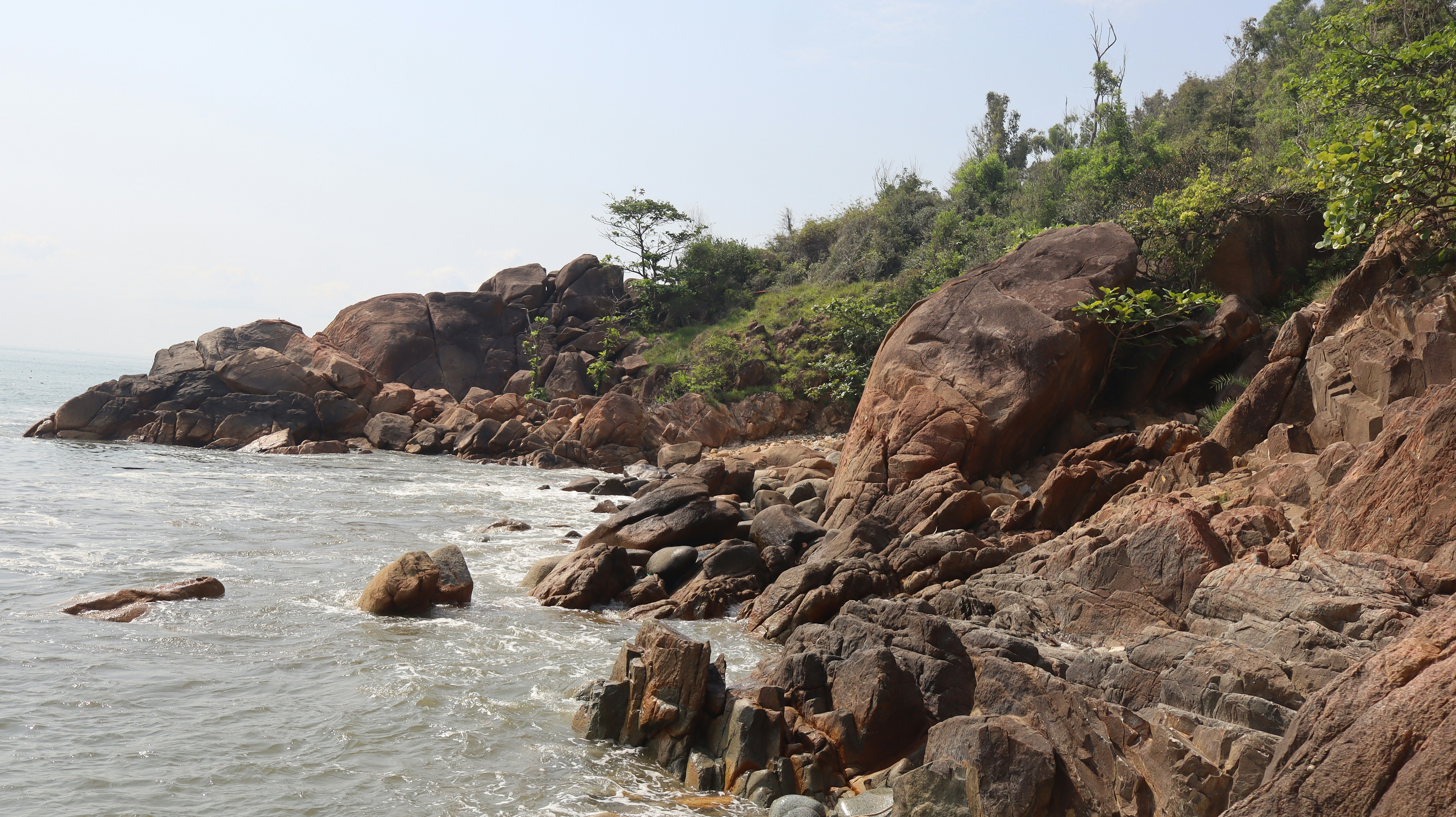 Rugged Shoreline: Sunlit Granite by Calm Tides