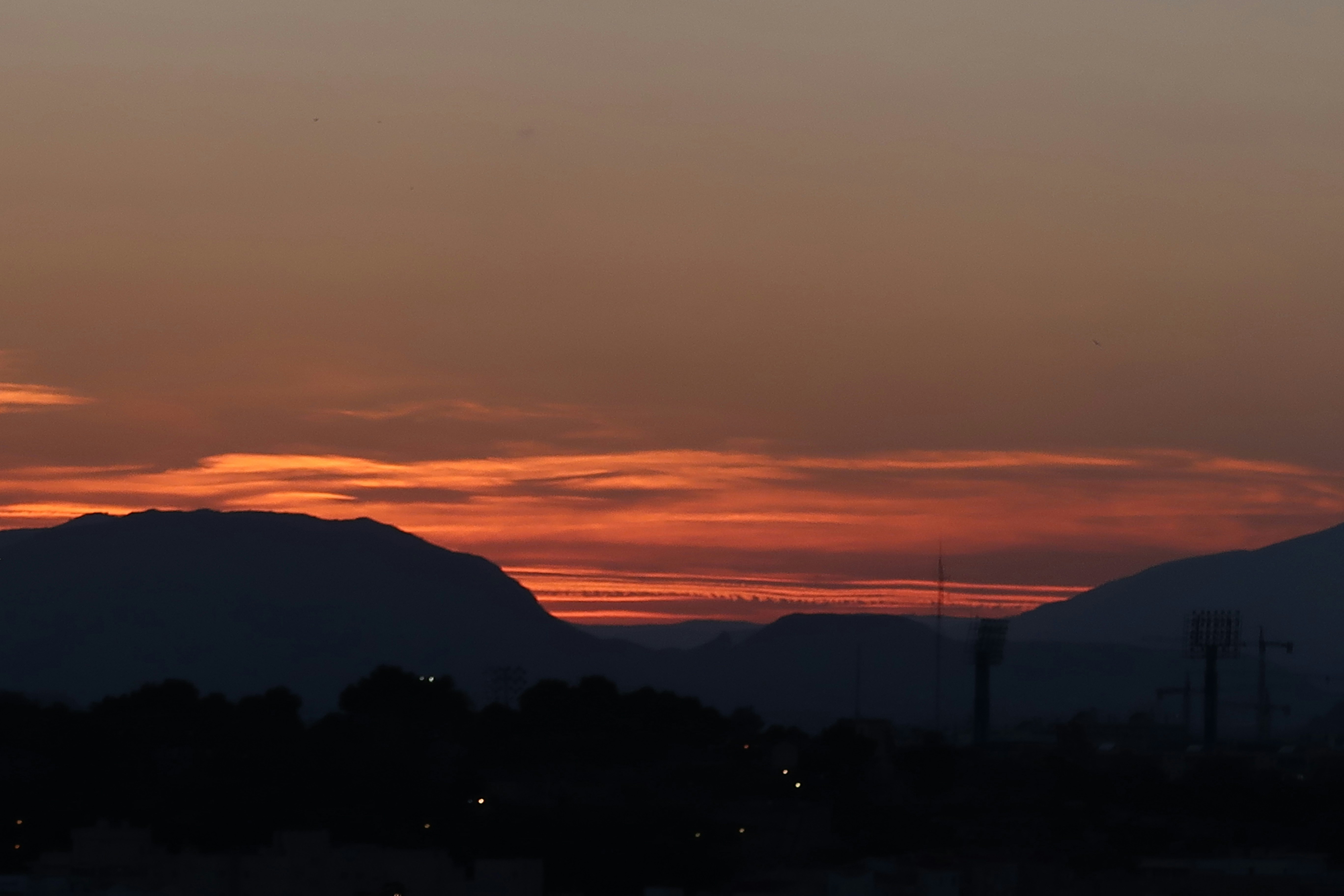 Silhouette Horizon at Dusk: City Lights Whispering Above the Ridge