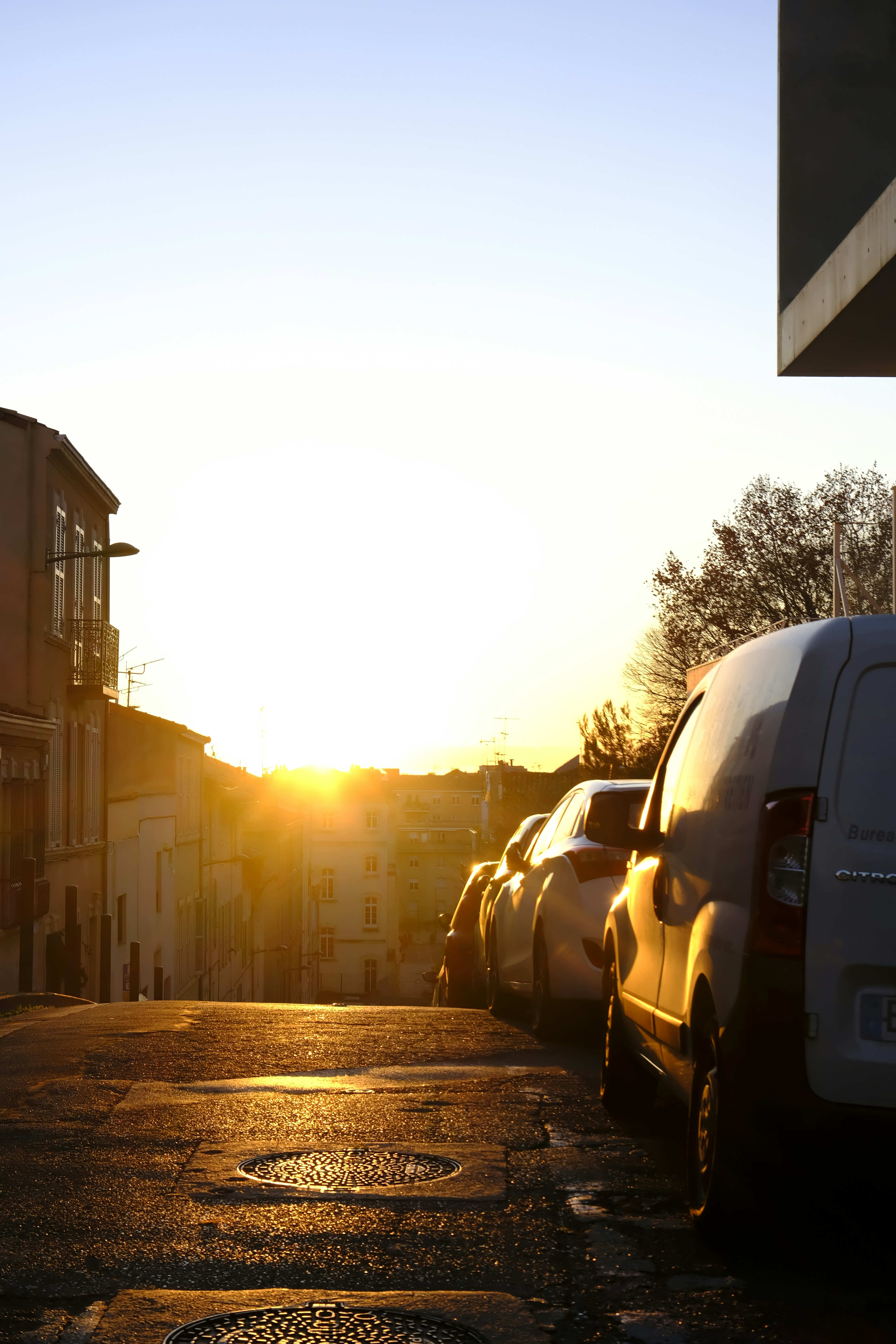 Sunlit Street Crest: A Quiet Morning Amid Parked Cars