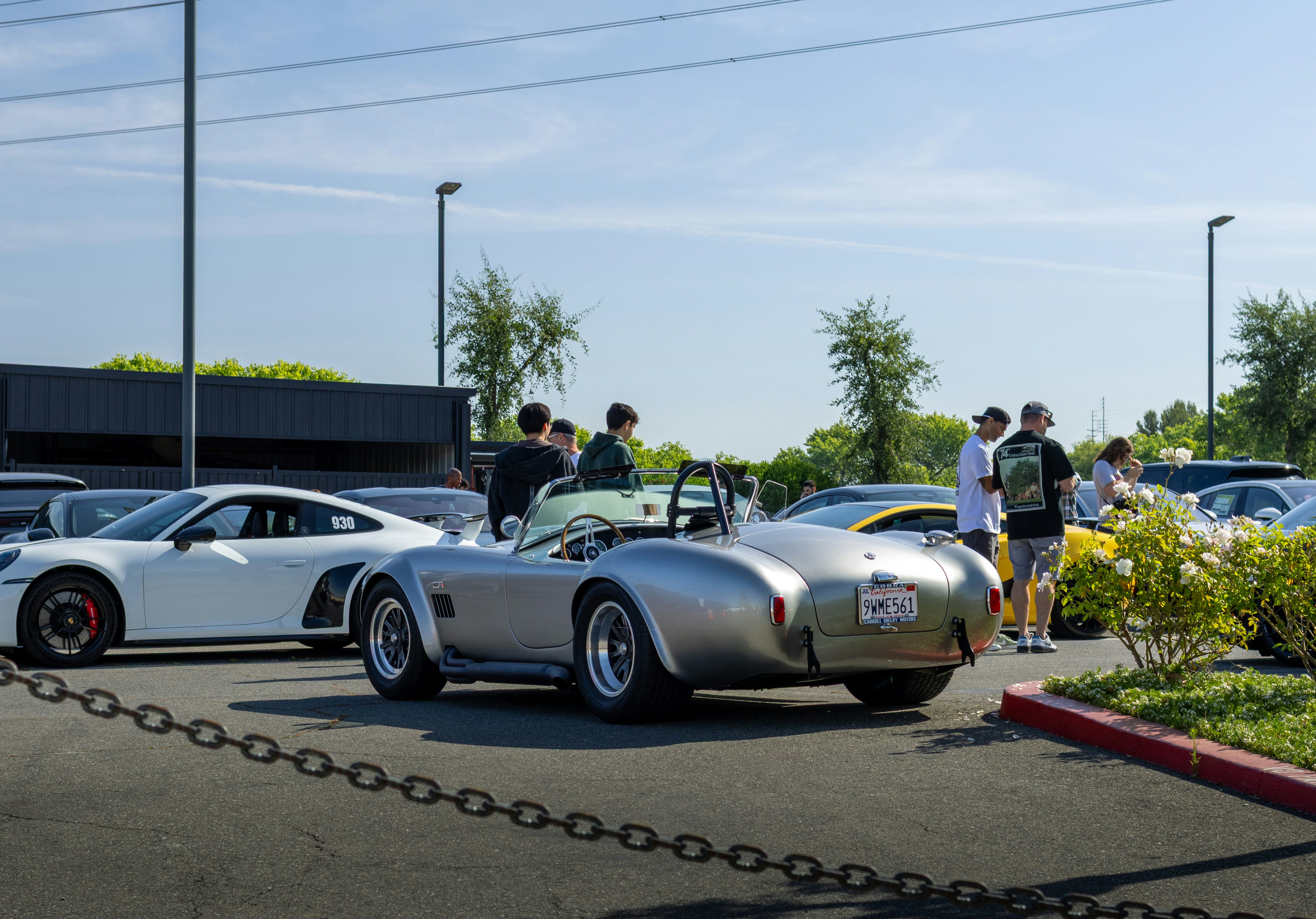 Sculpted silver roadster under casual car-club chatter