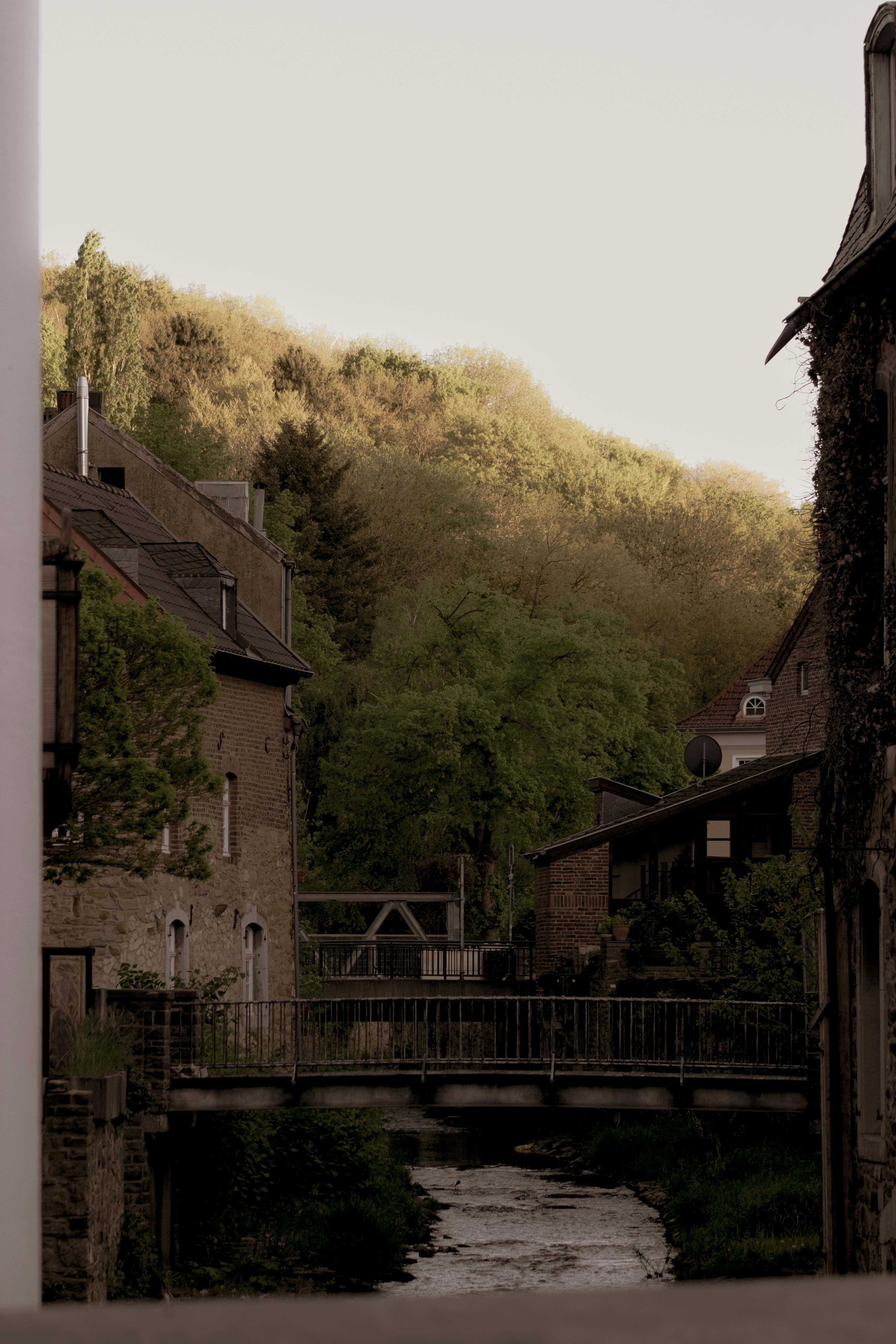 Sunlit Village Canal Framed by Old Brick and Verdant Hills