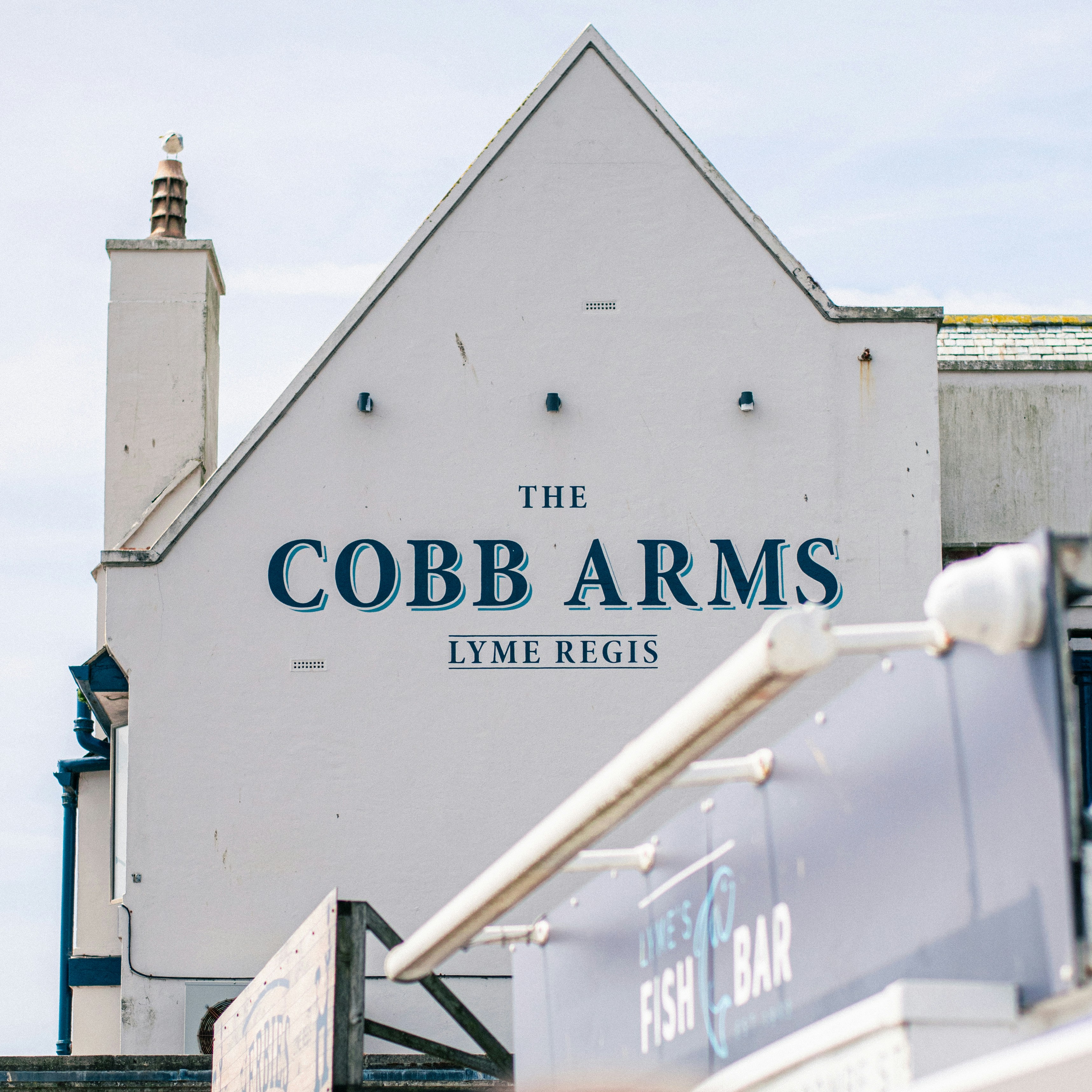 The Cobb Arms Sign: Coastal Pub Facade Warmed by Early Light
