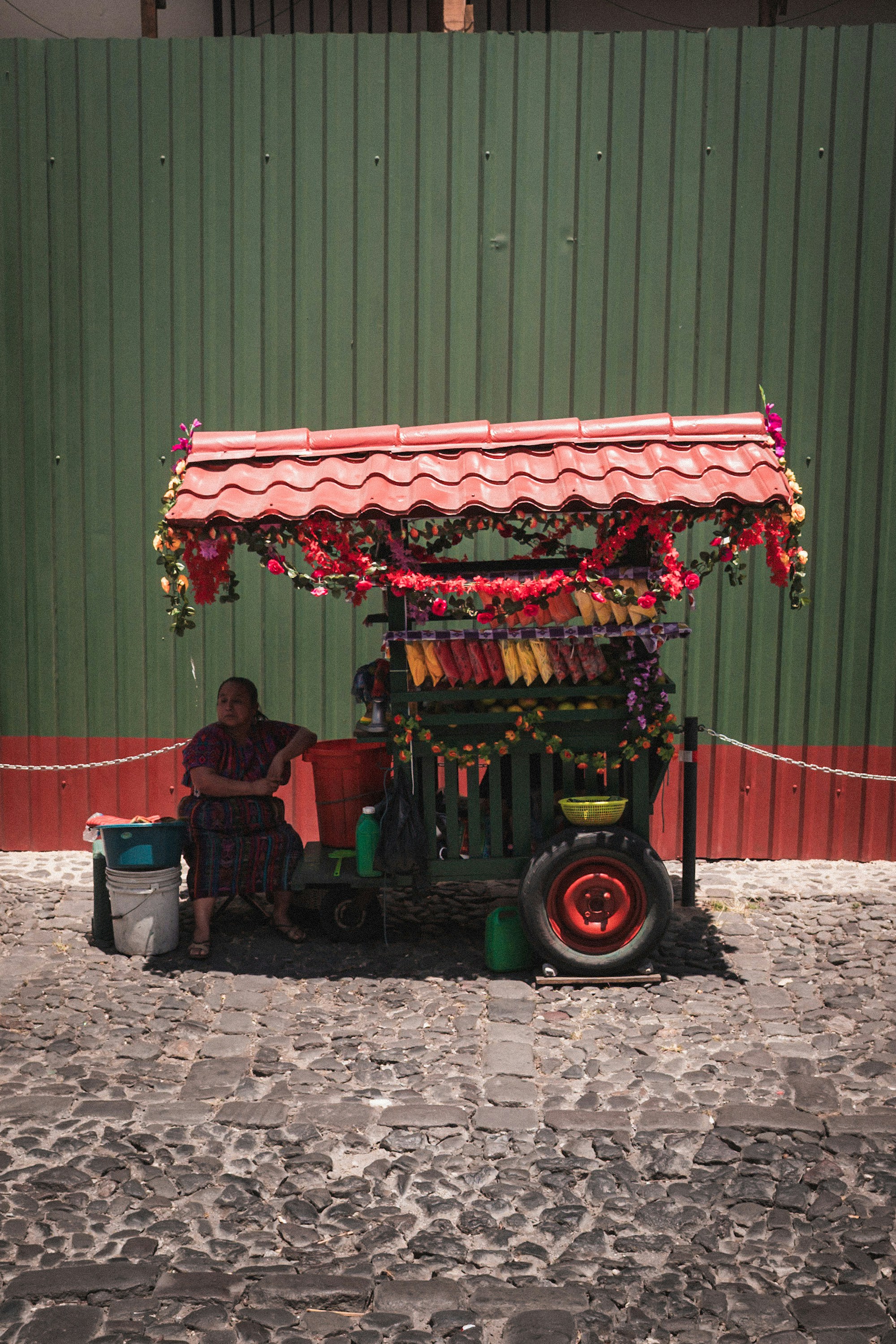 Colorful street cart under a tiled canopy against a green corrugated wall