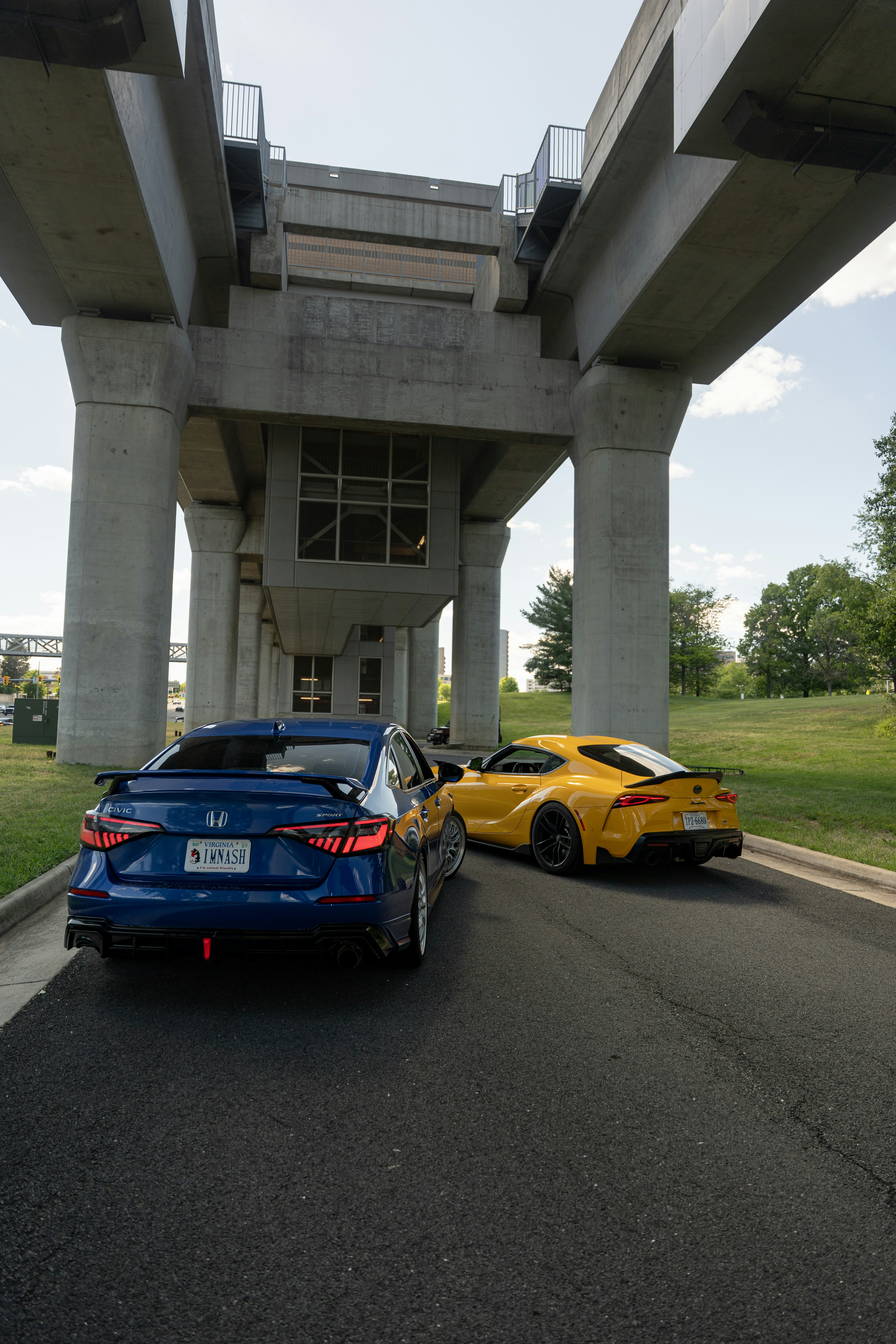 Under the Overpass: Blue Honda and Yellow Porsche Meet on a Quiet Road