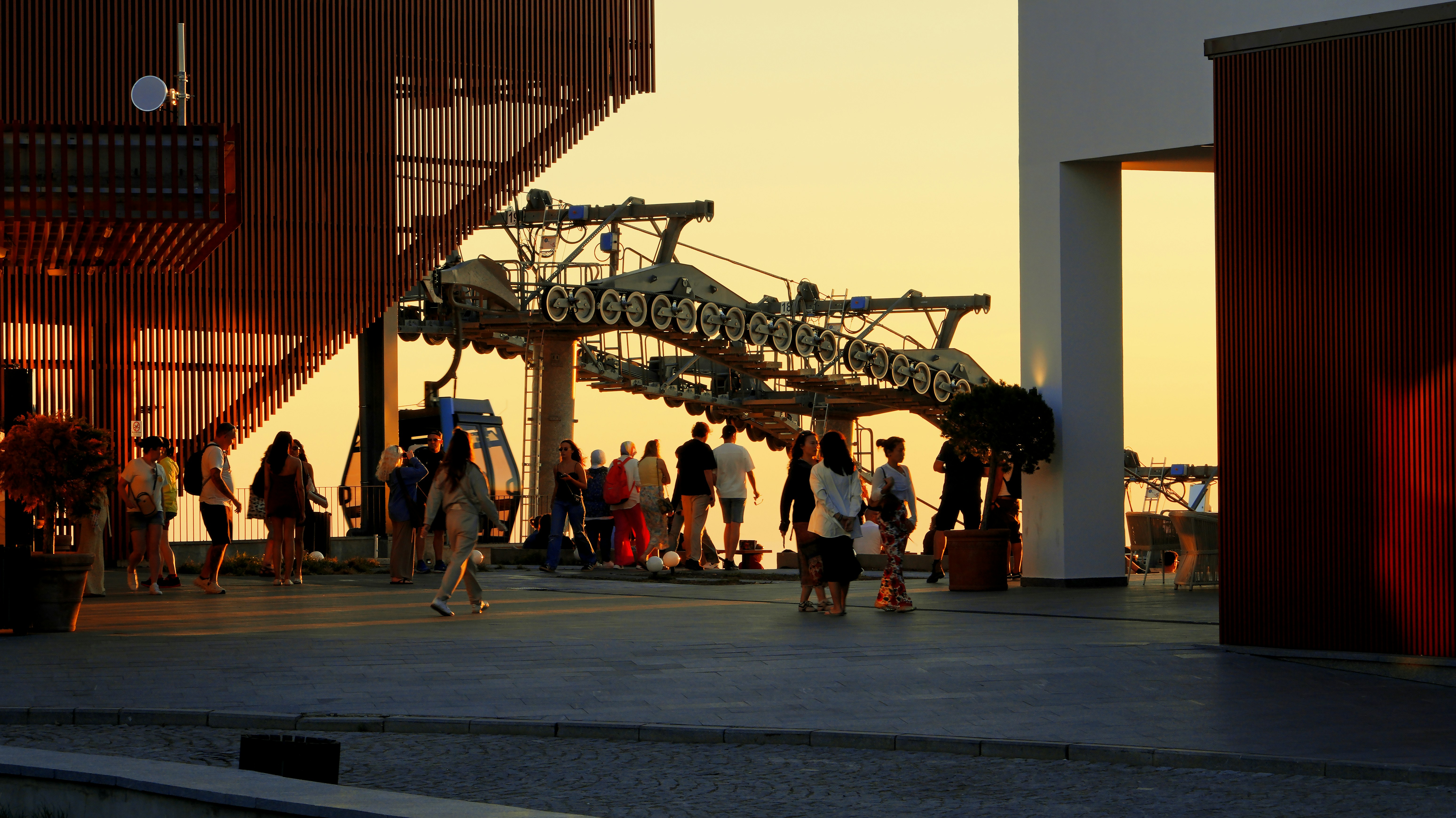 Sunlit promenade beneath ornate archway as crowds gather at golden hour