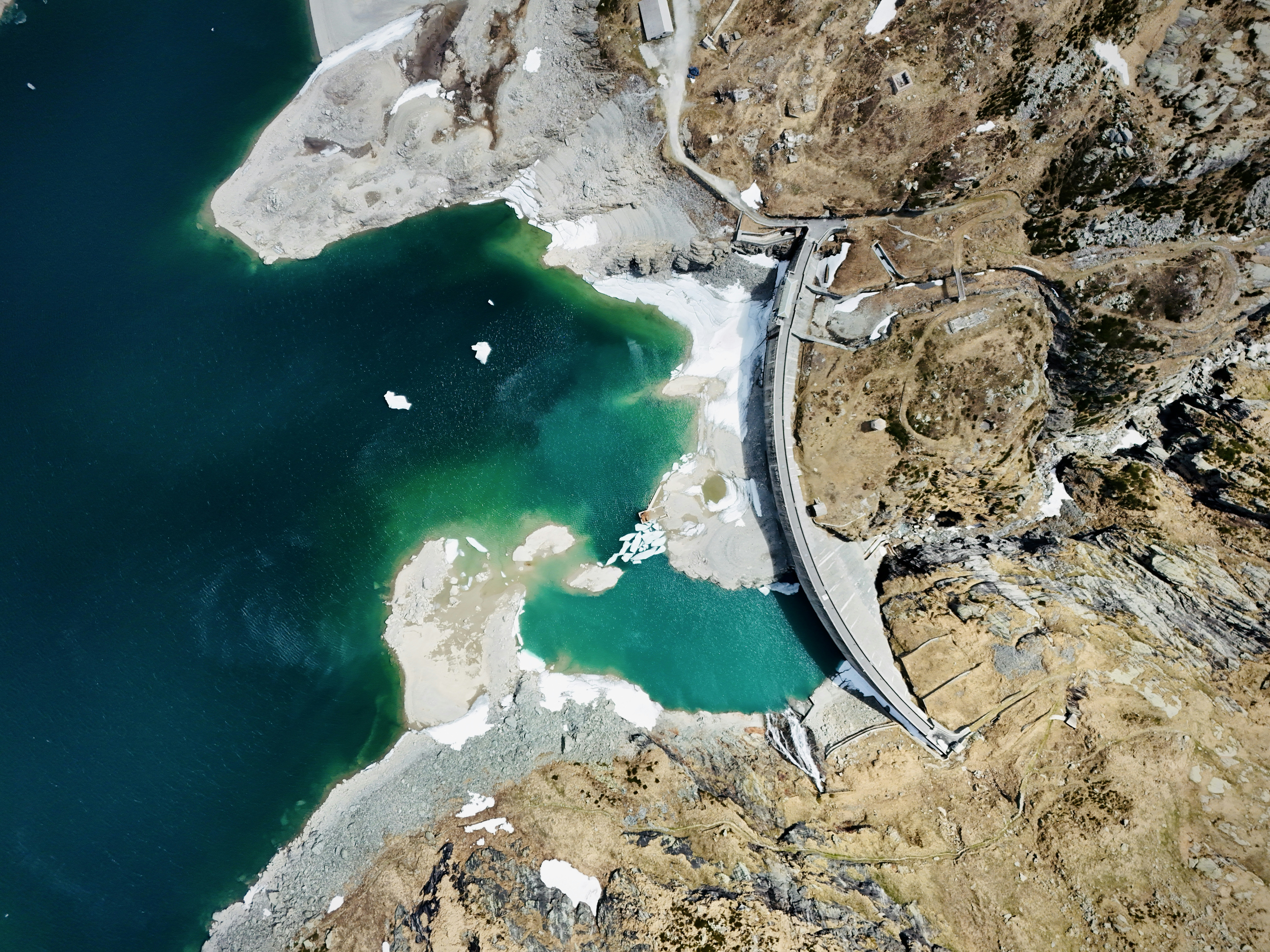 Aerial Curve: A Dam and Turquoise Inlet Carved into Arid Cliffs