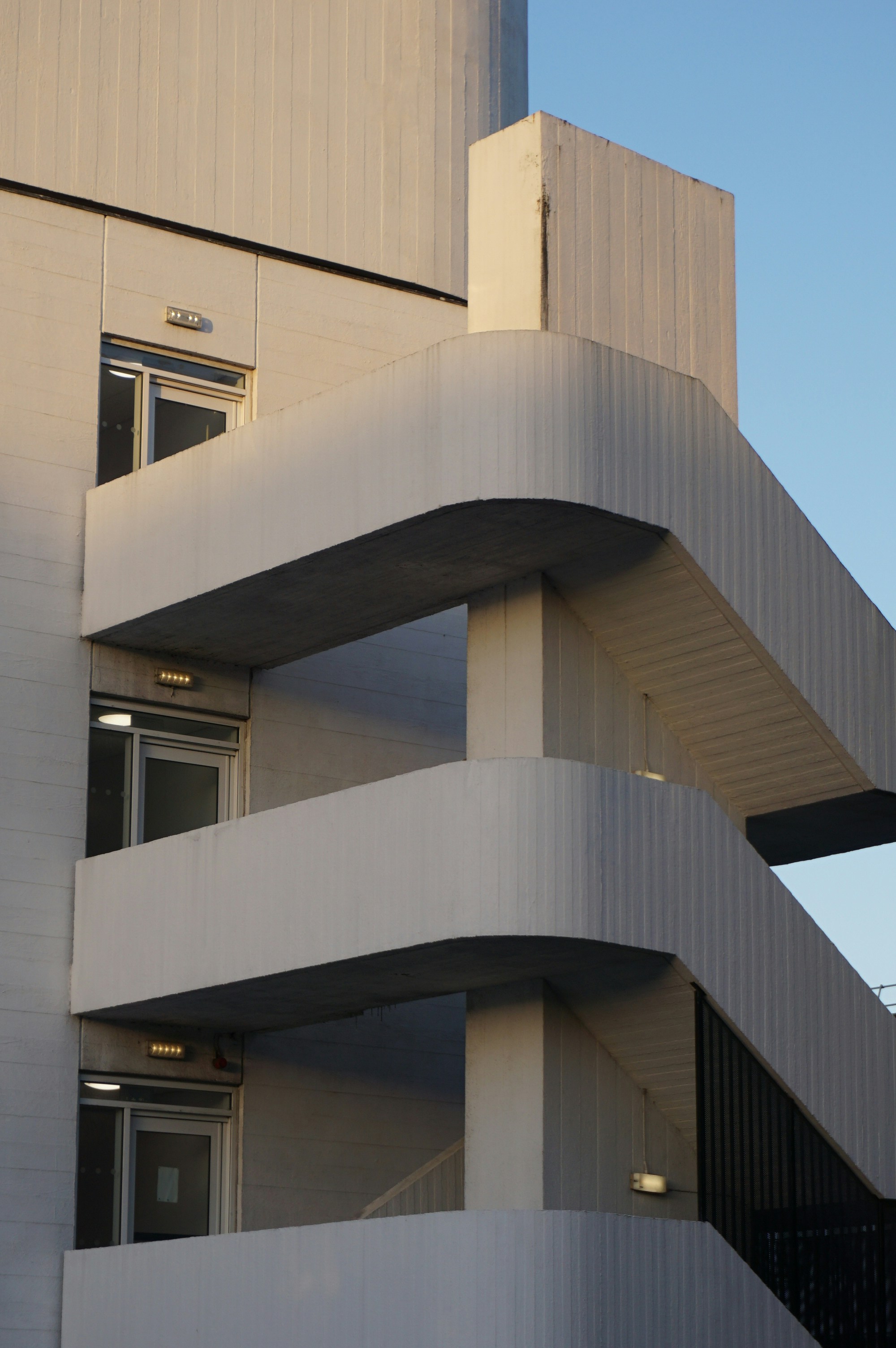 Curved Concrete Ribbons Ascend the Sunlit Facade