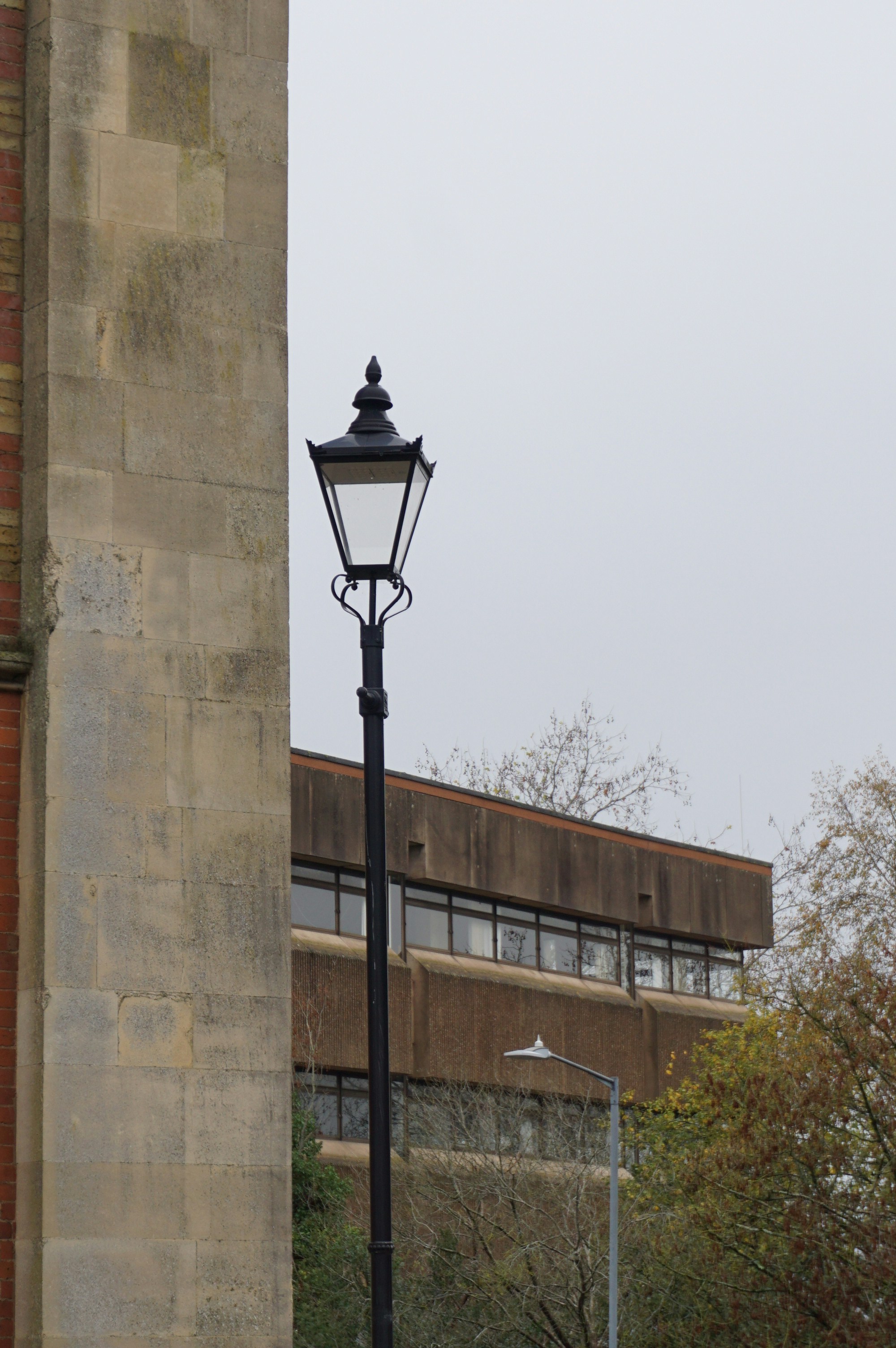 A lone street lamp rises beside a weathered stone wall