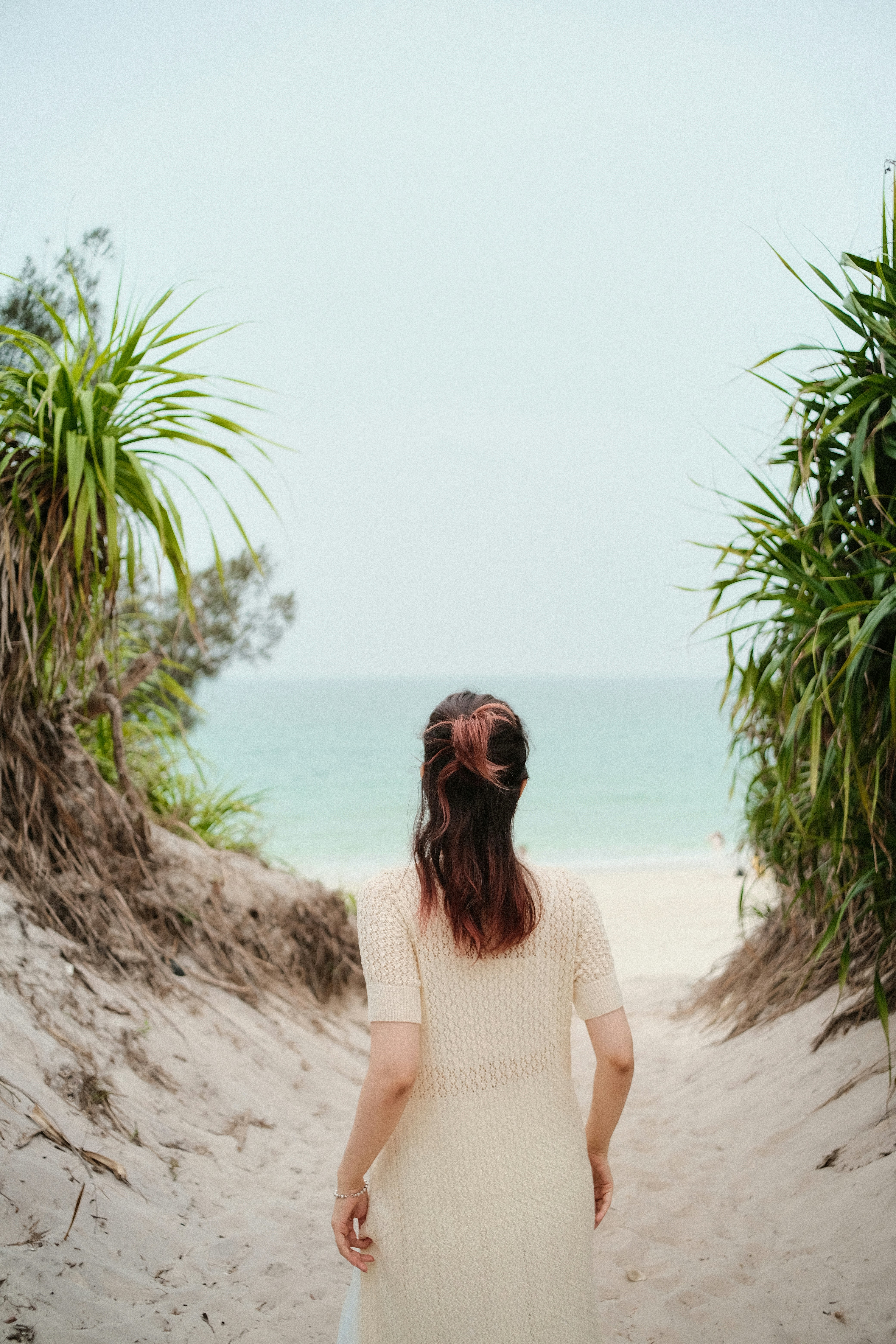 Path to the Sea: A Woman in a White Dress Walking Toward the Ocean Gate