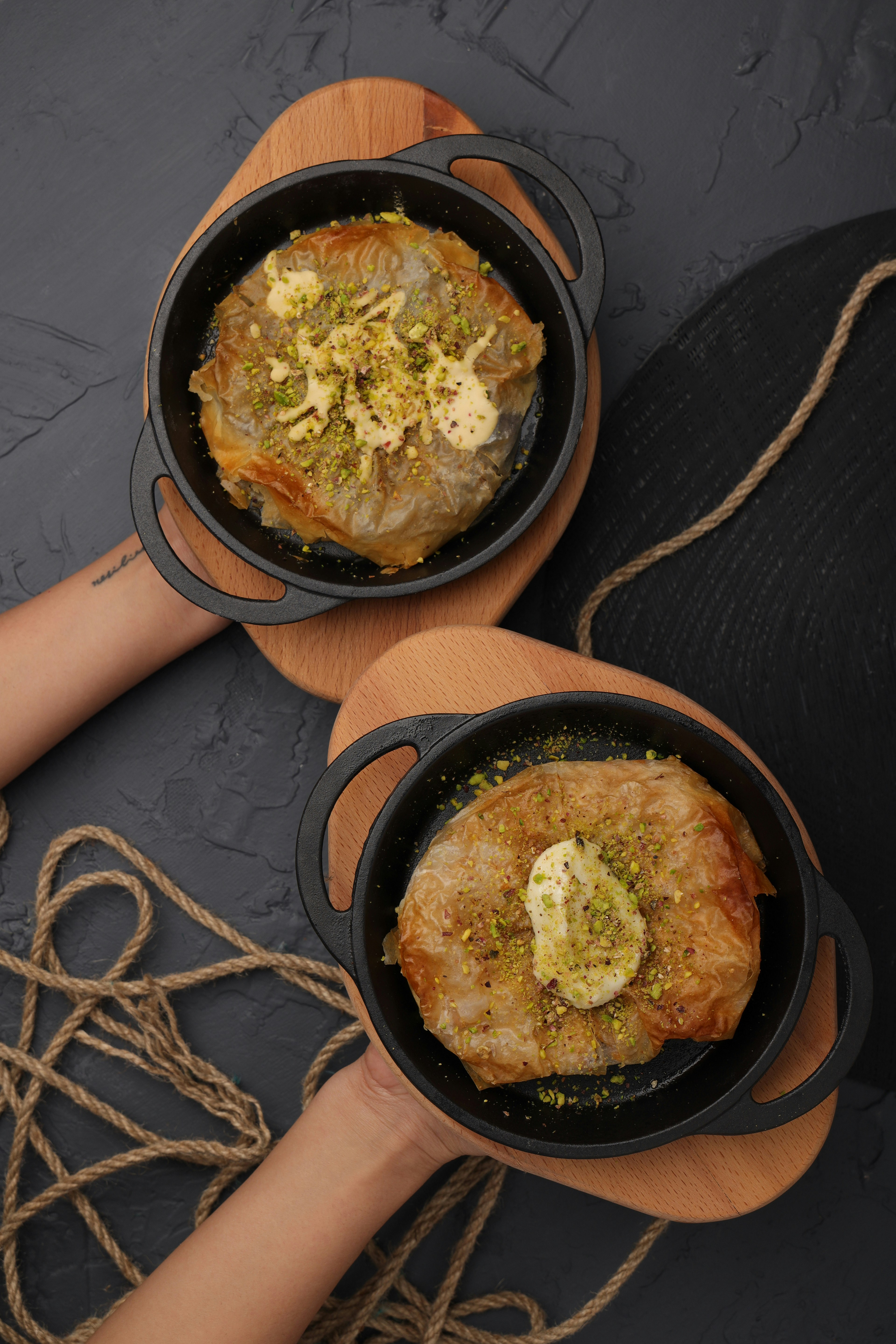 Dual Cast Iron Dishes: Two Crispy Bakes Sizzling on a Rope-Annulated Board