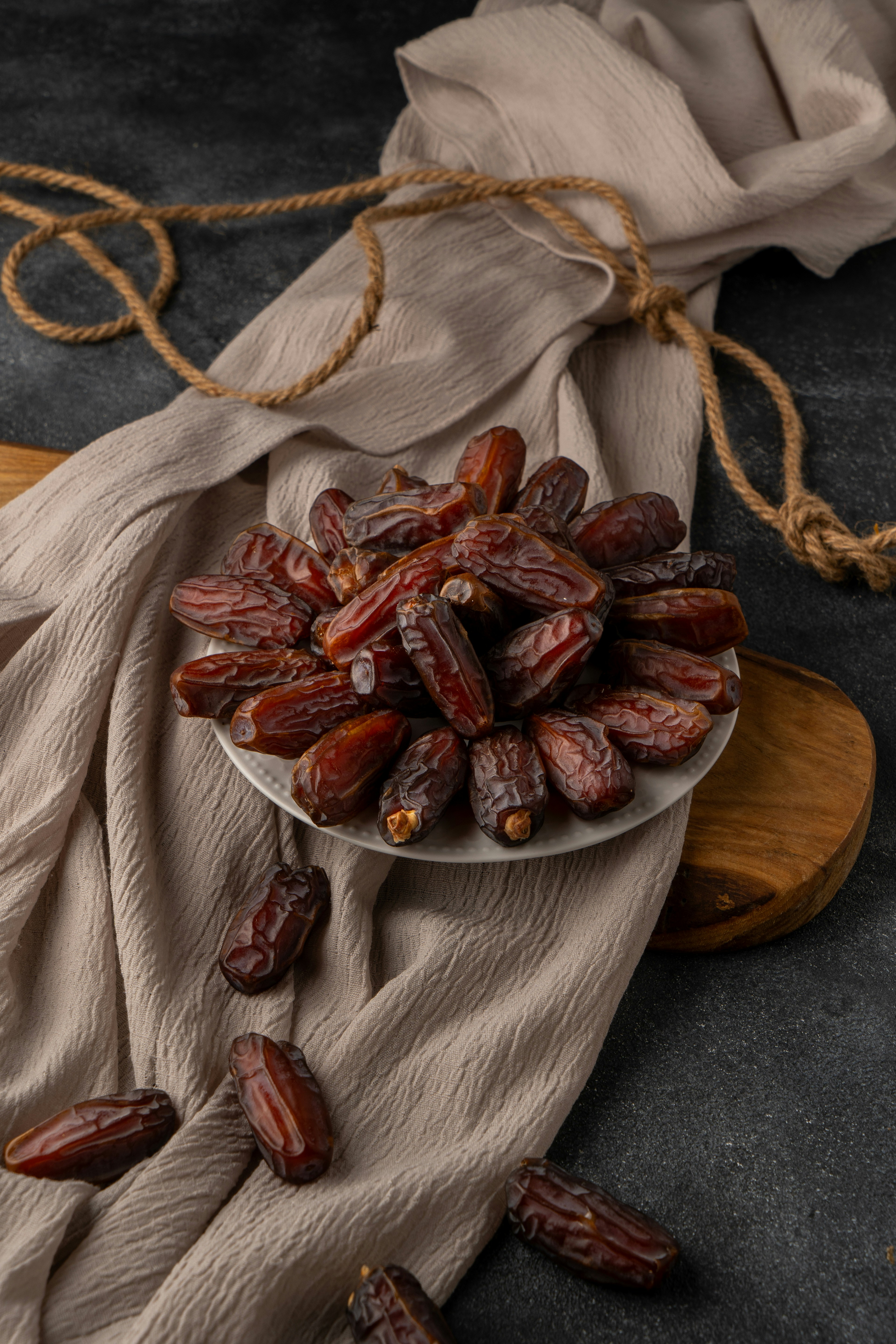 Plate of glossy dates nestled on soft linen with rustic twine