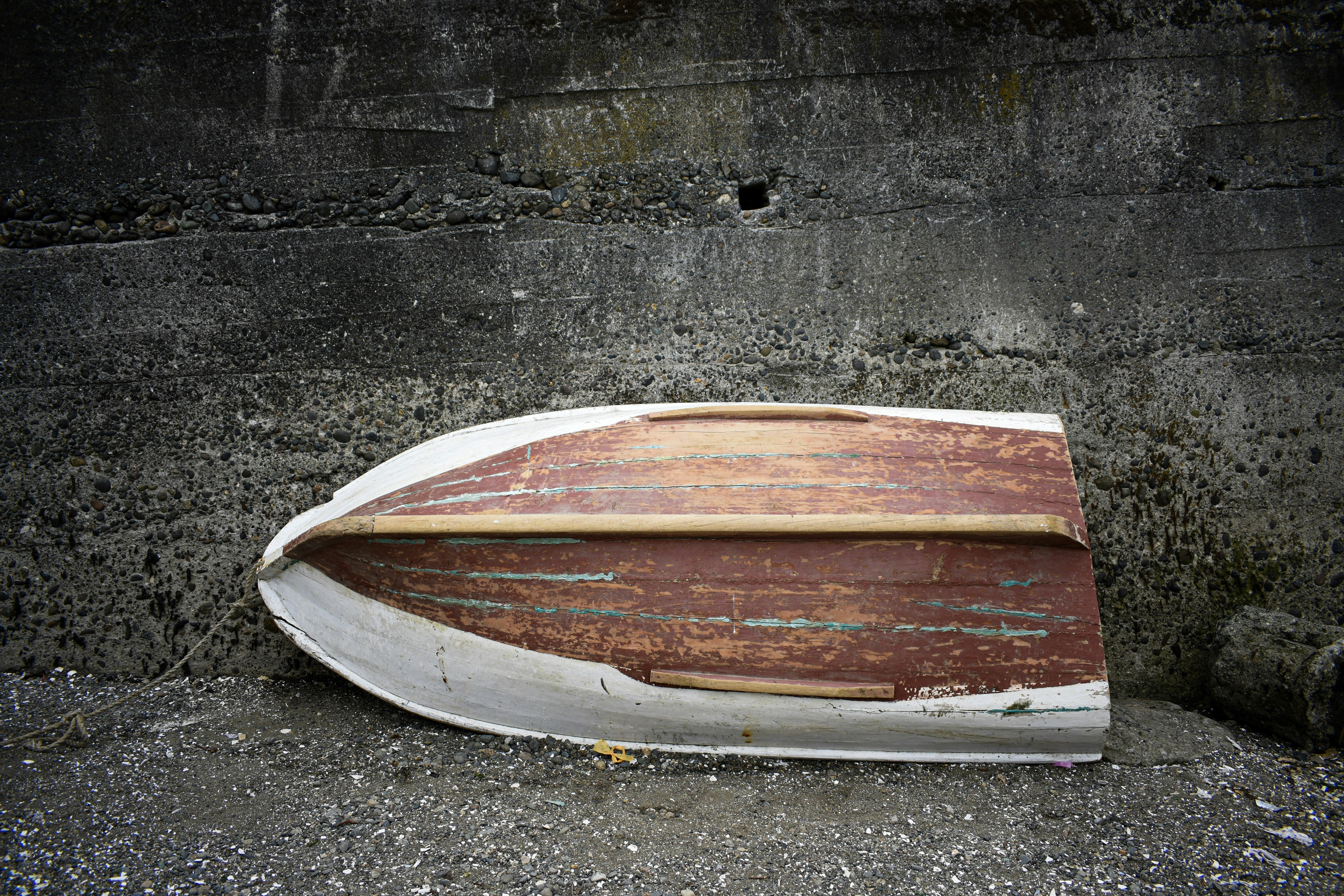 Weathered dinghy on a gritty shoreline wall