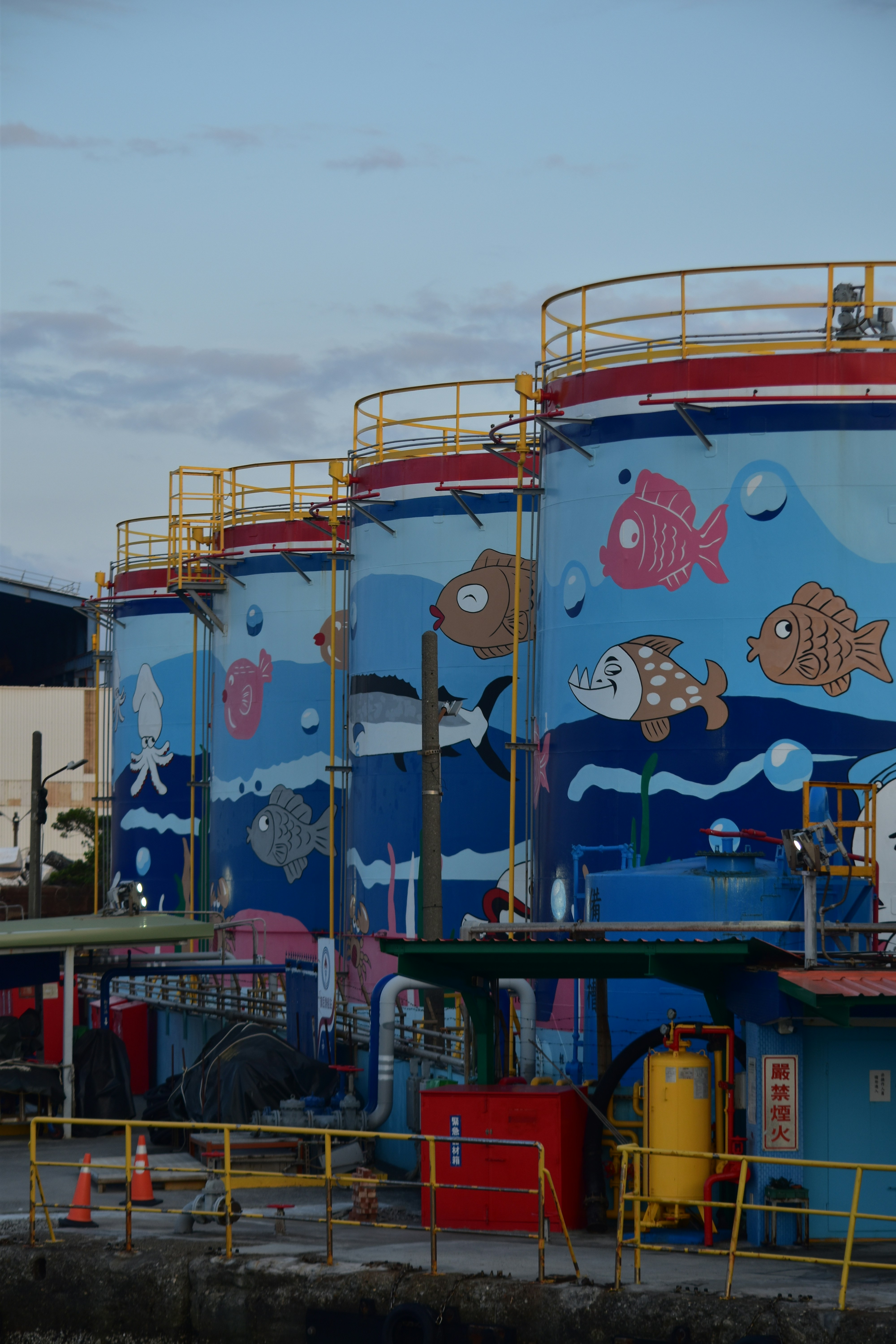Industrial Ocean: Colorful Tanks Adorned with Playful Fish Murals