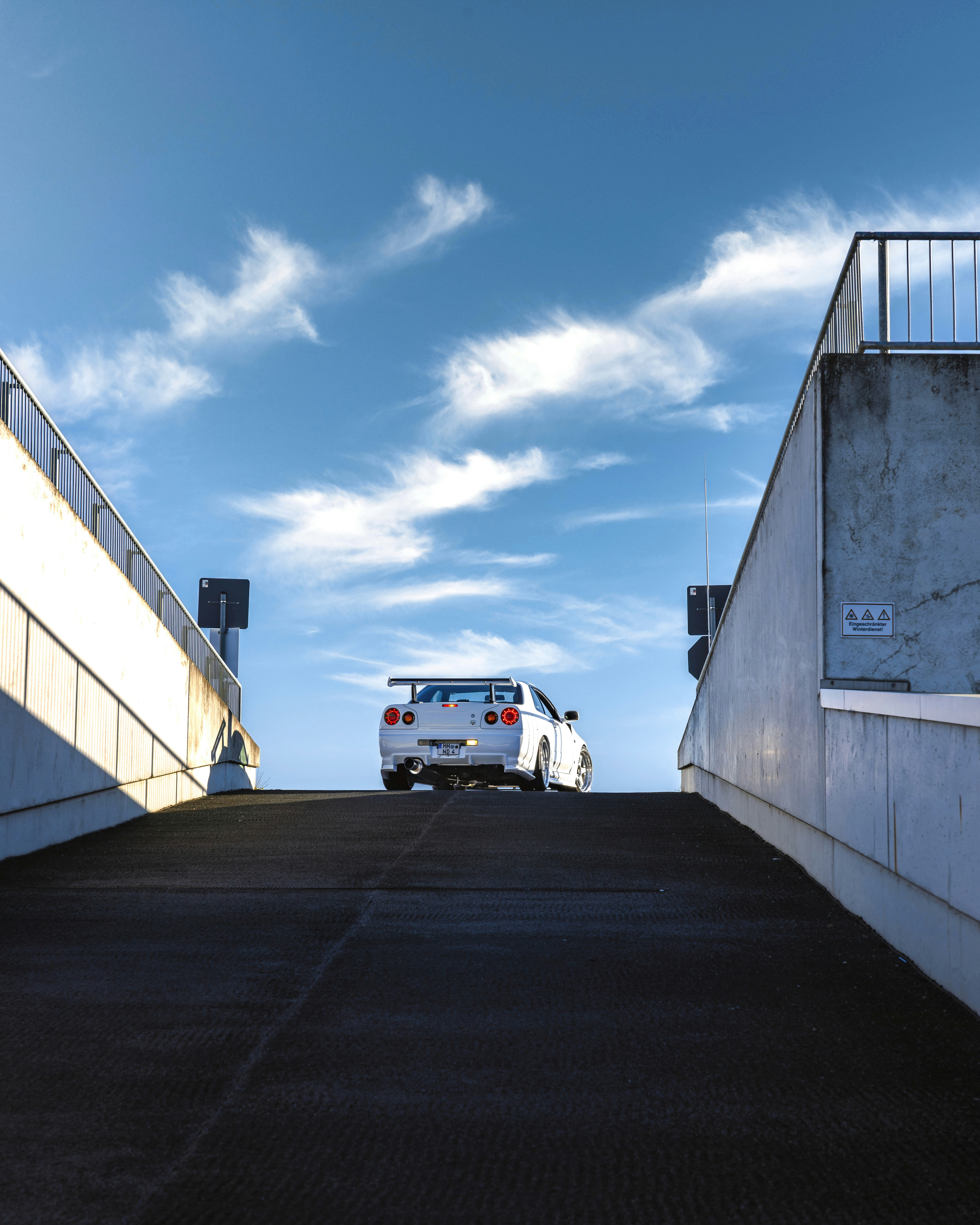 White Sports Car Cresting a Concrete Ramp Under a Sky of Blue Whispers