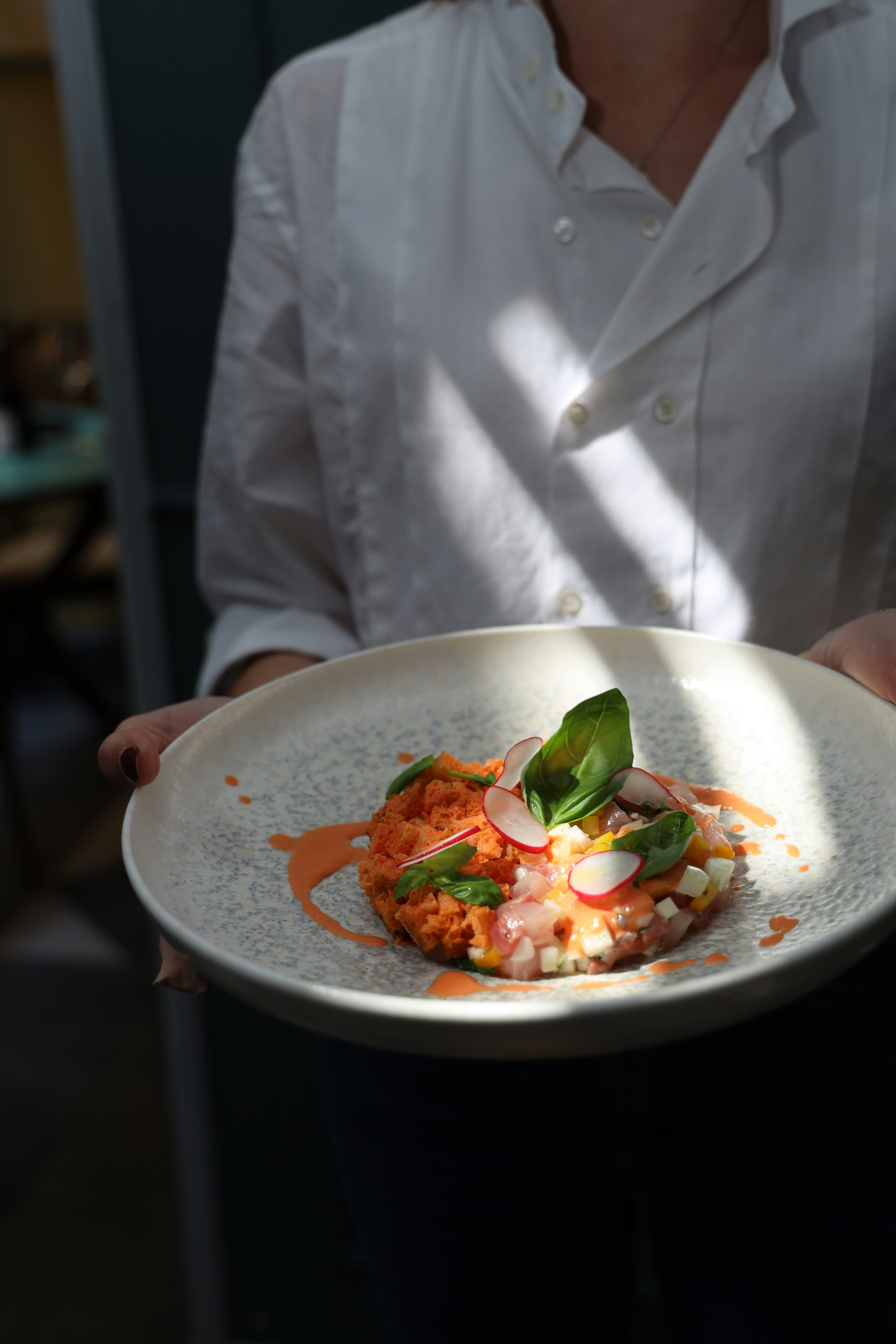 Plate with vibrant garnish: a chef’s plated artistry in white shirt light behind