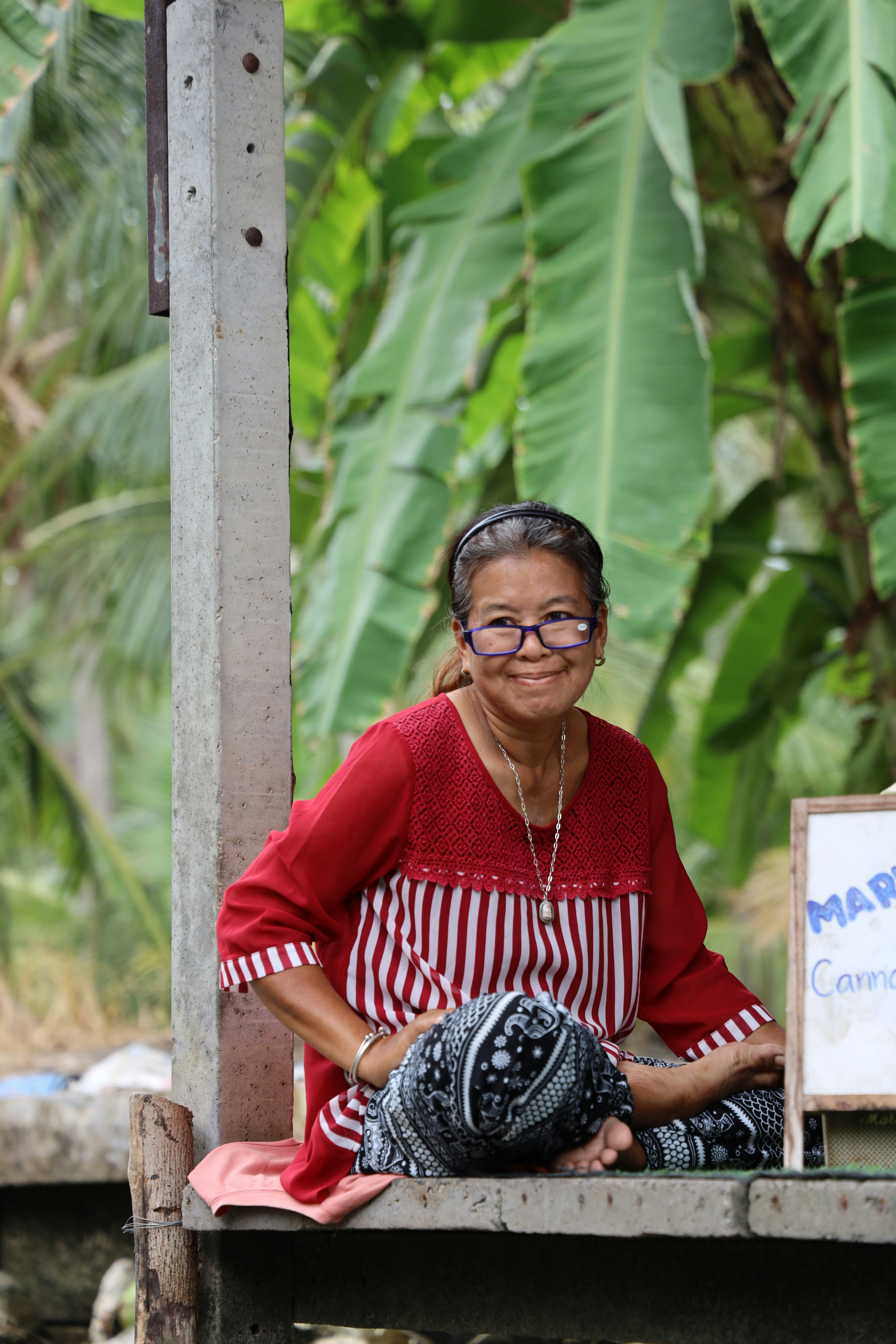 Smiling vendor by a banana-leaf backdrop