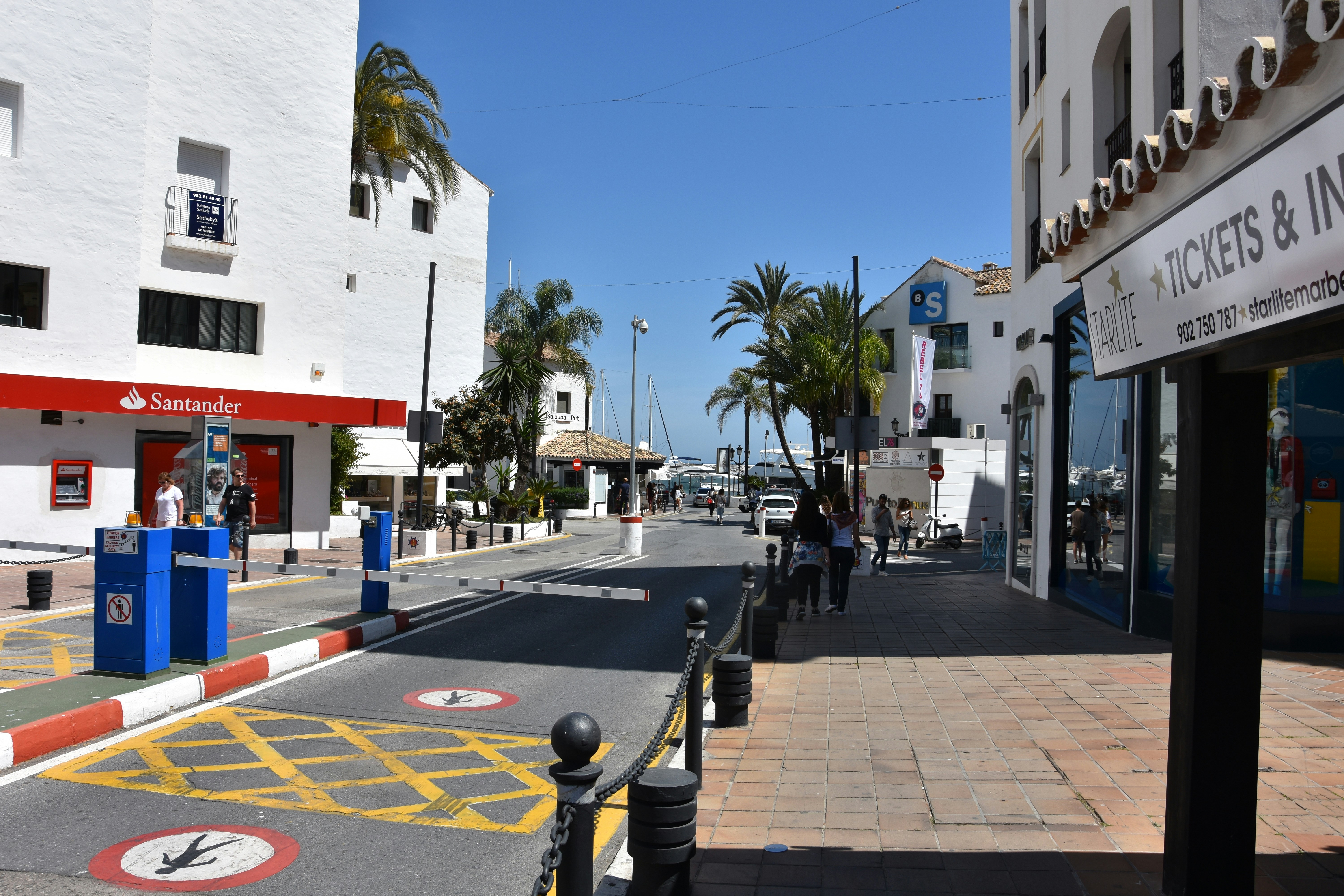 Sunlit promenade with bustling storefronts and tranquil sea beyond