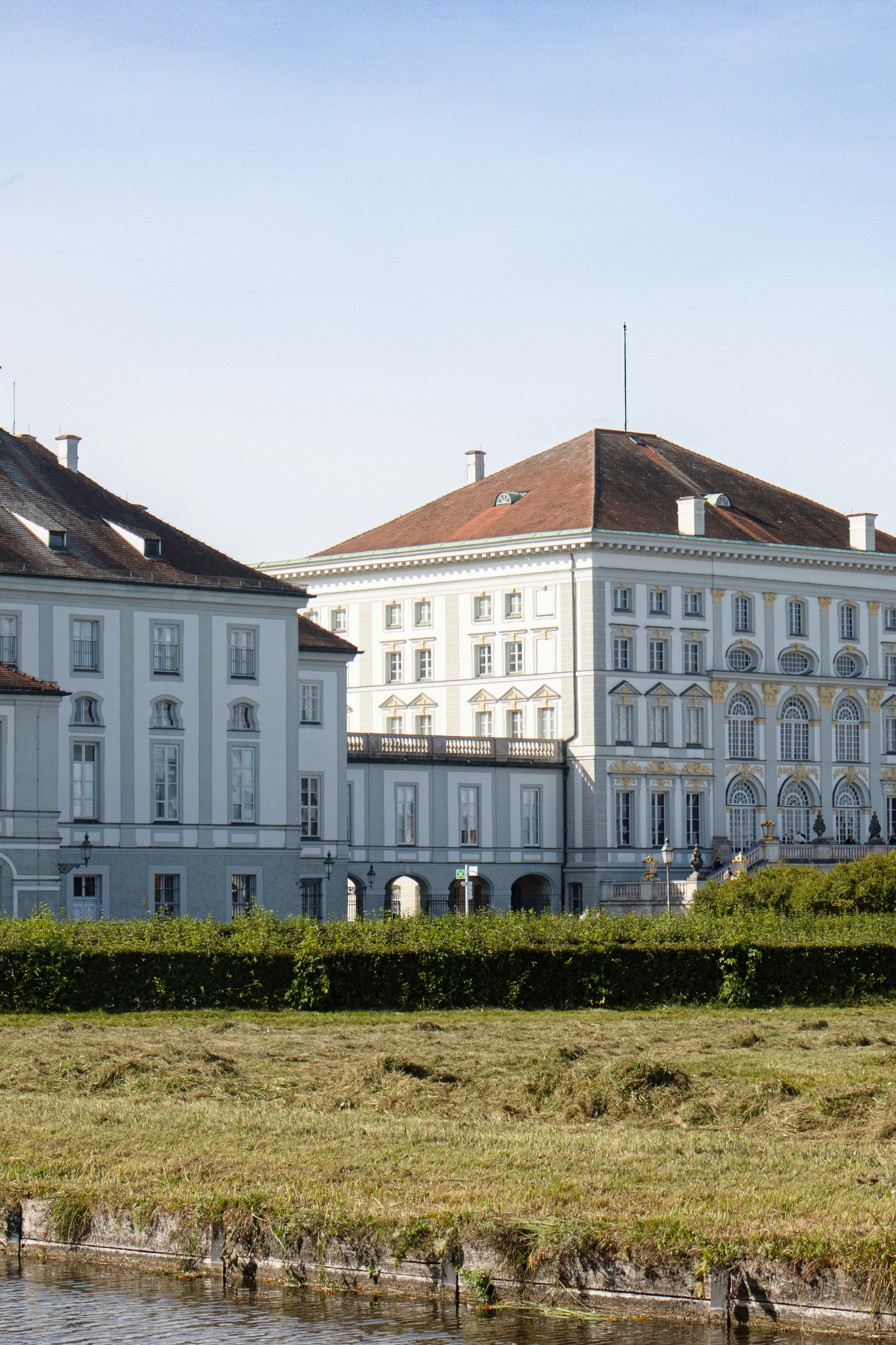 Elegant riverside façade: a pale European manor under a clear sky