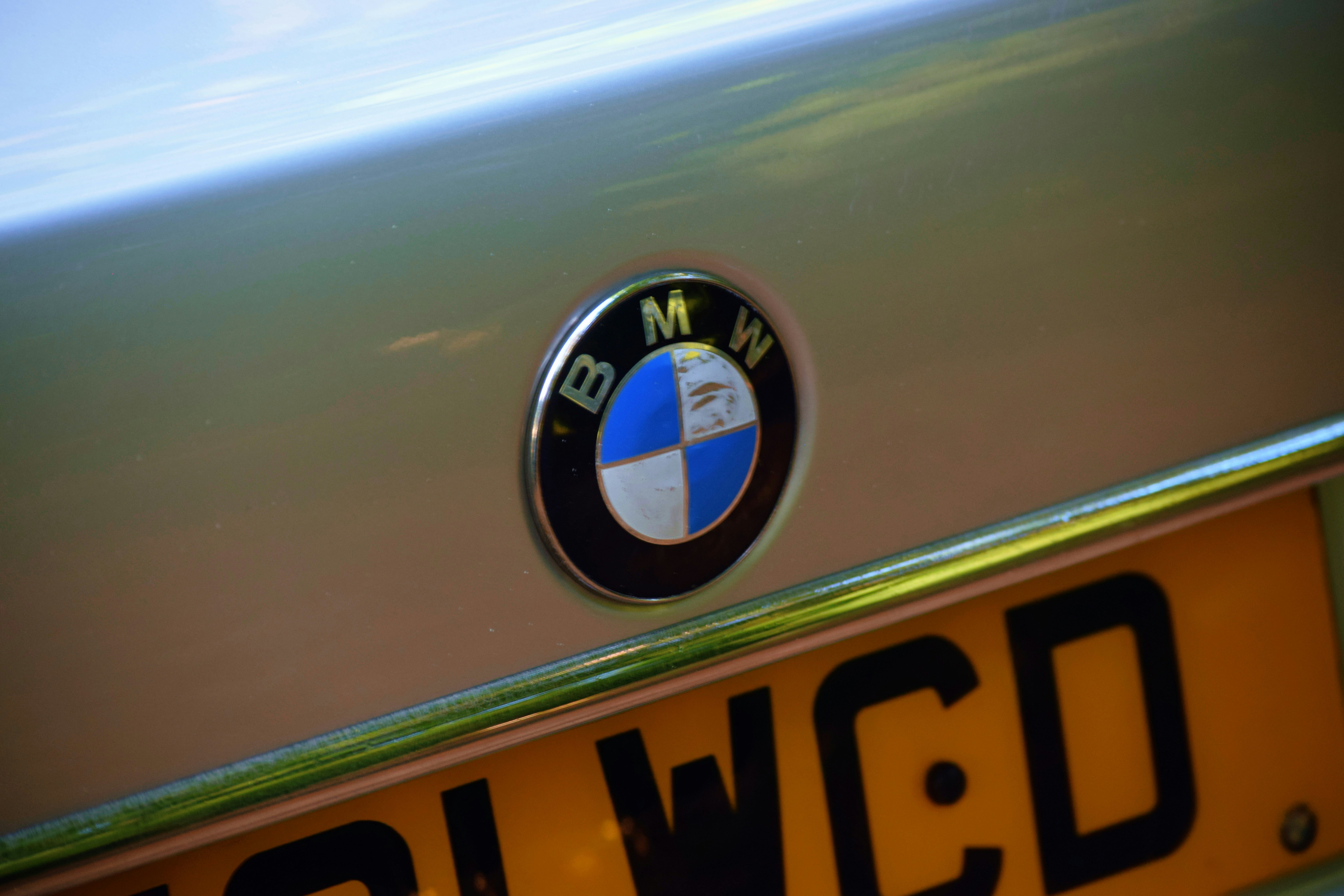 BMW badge and license plate glow on a chrome tail of a sunlit car