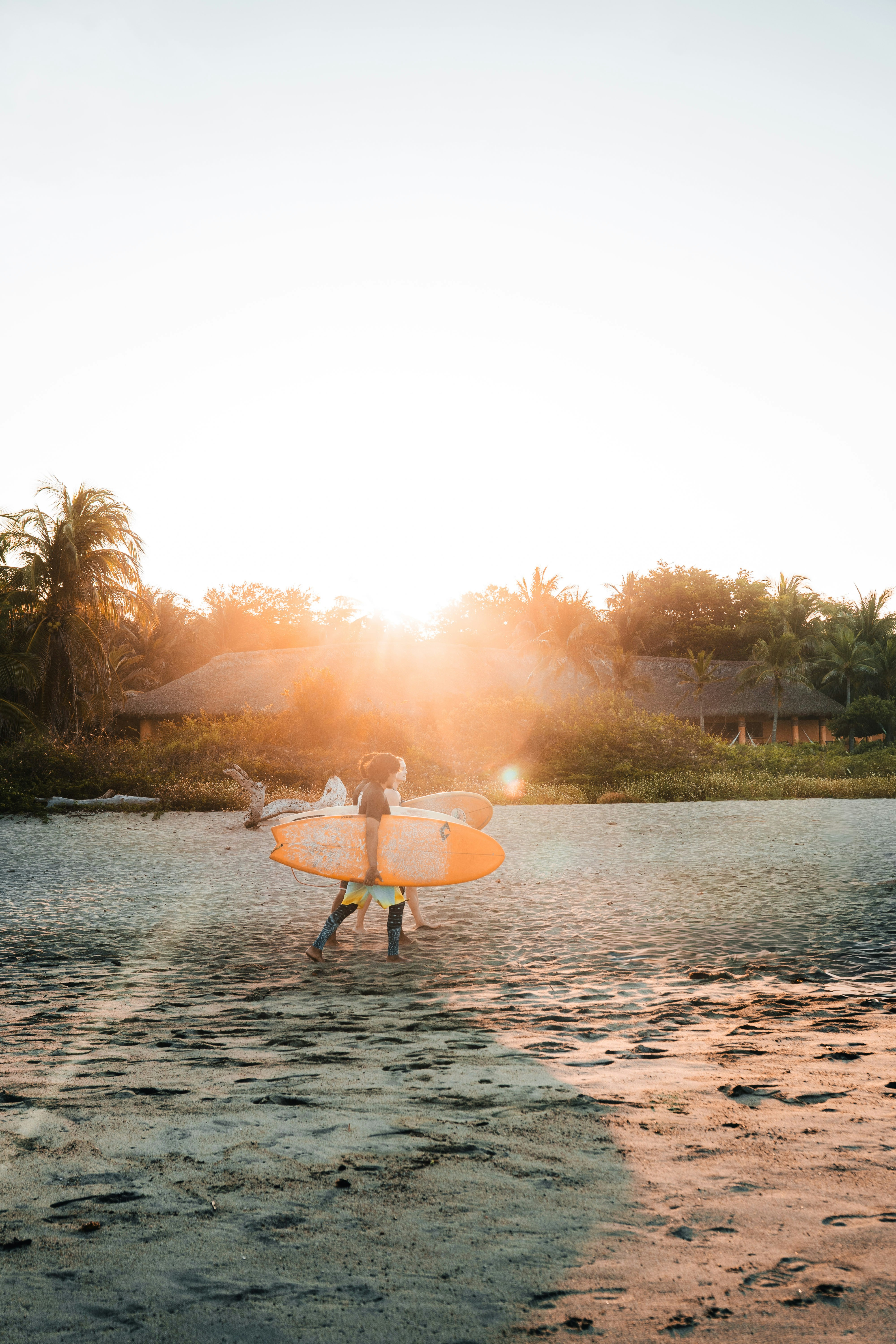 Surfing Sunset: Two surfers wade toward shore with glowing light