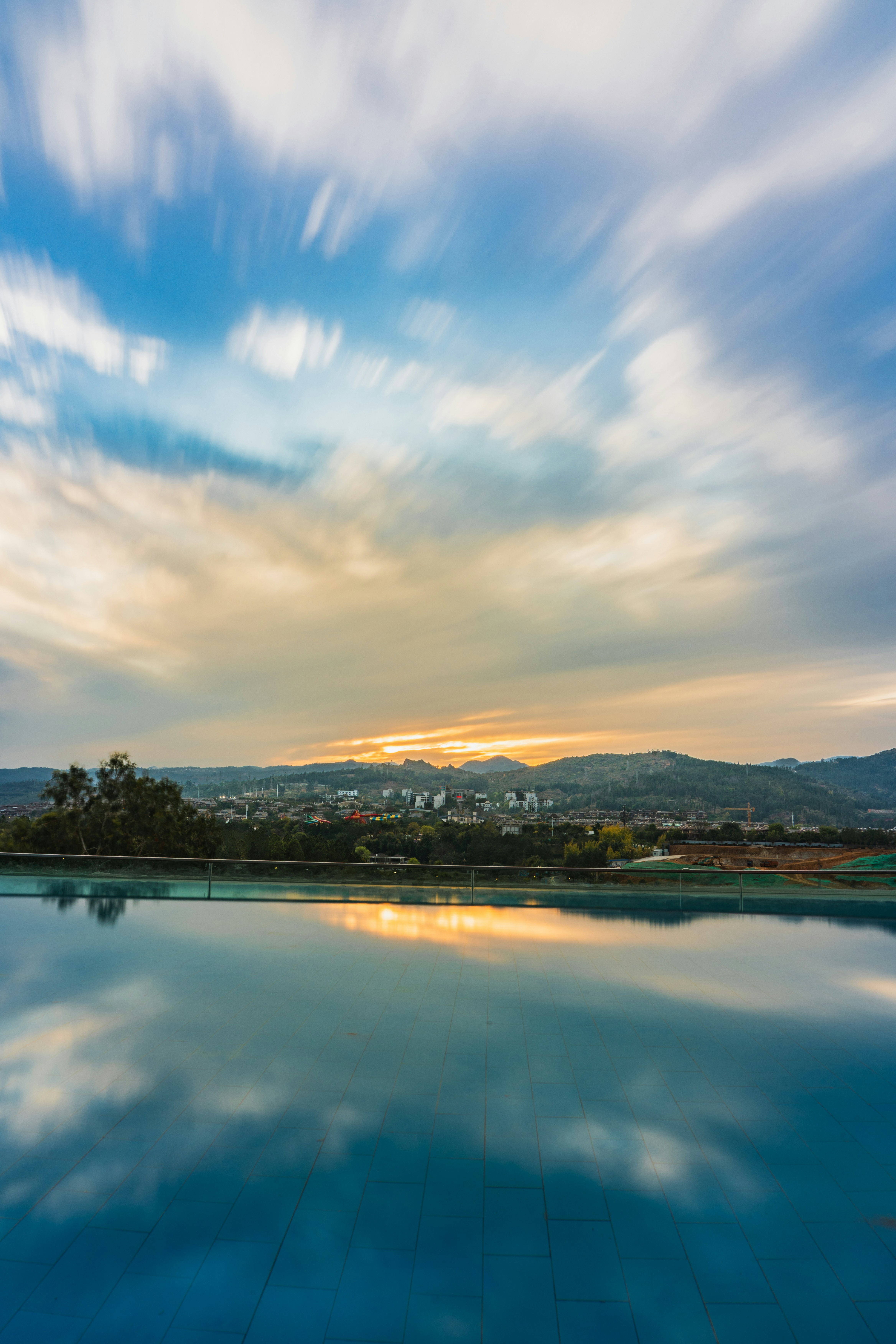 Sunset Over the Pool: Skyward Reflections and Distant Hills