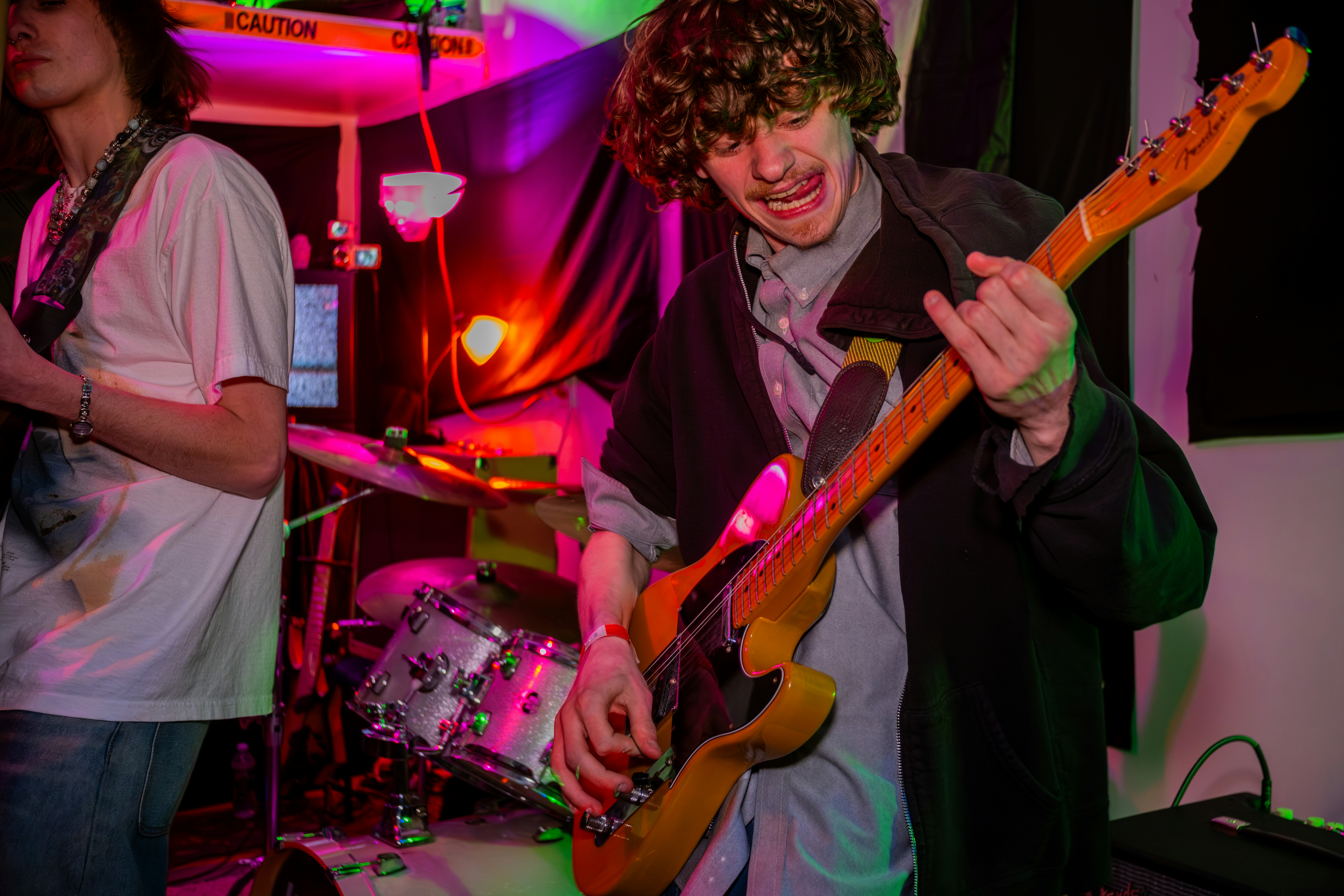 Twilight Riffs: A guitarist grips the neck of a sunlit bass under neon stage lights