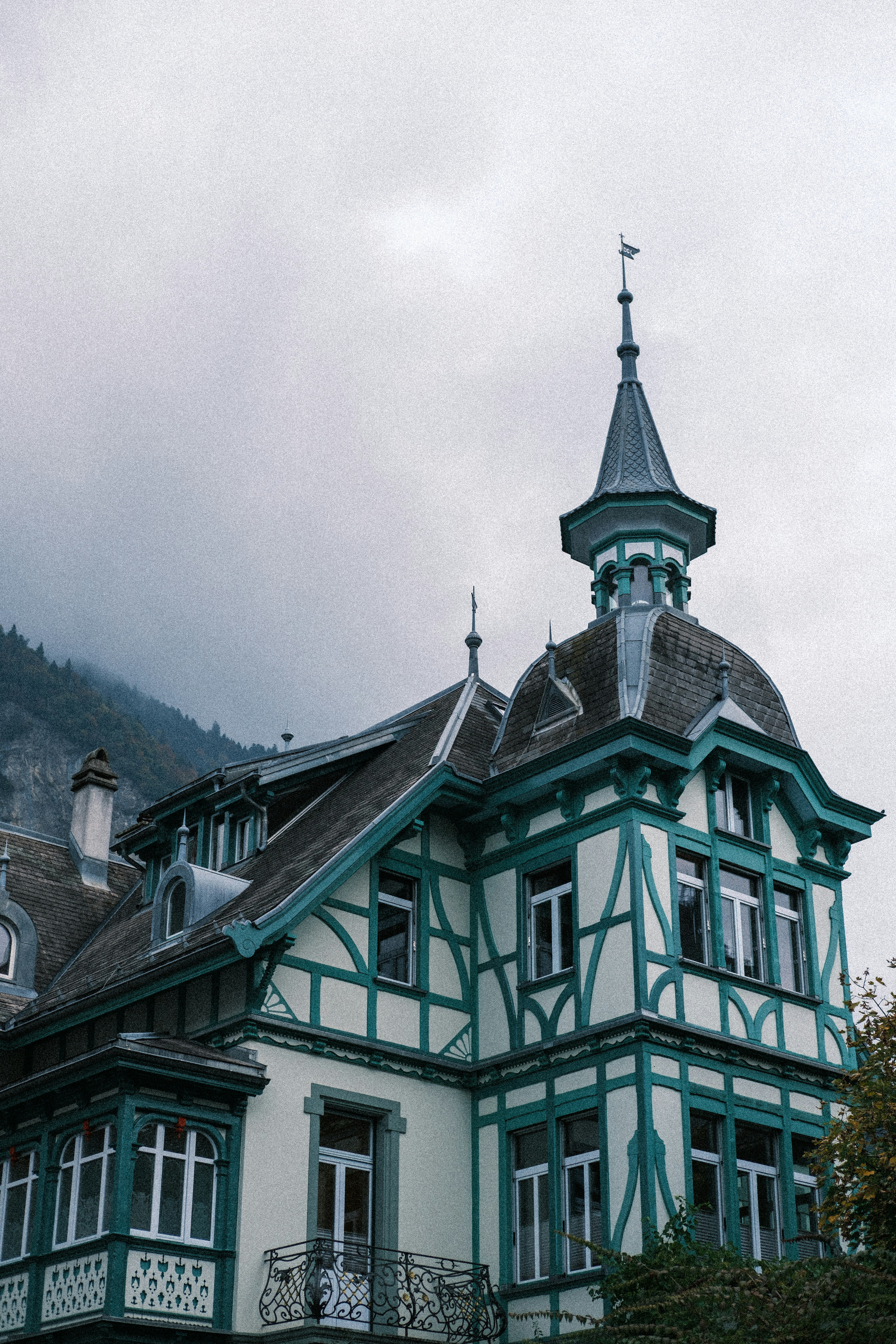 Haunted Manor in Mint and Slate: Tudor Timbered Facade against Misty Hills