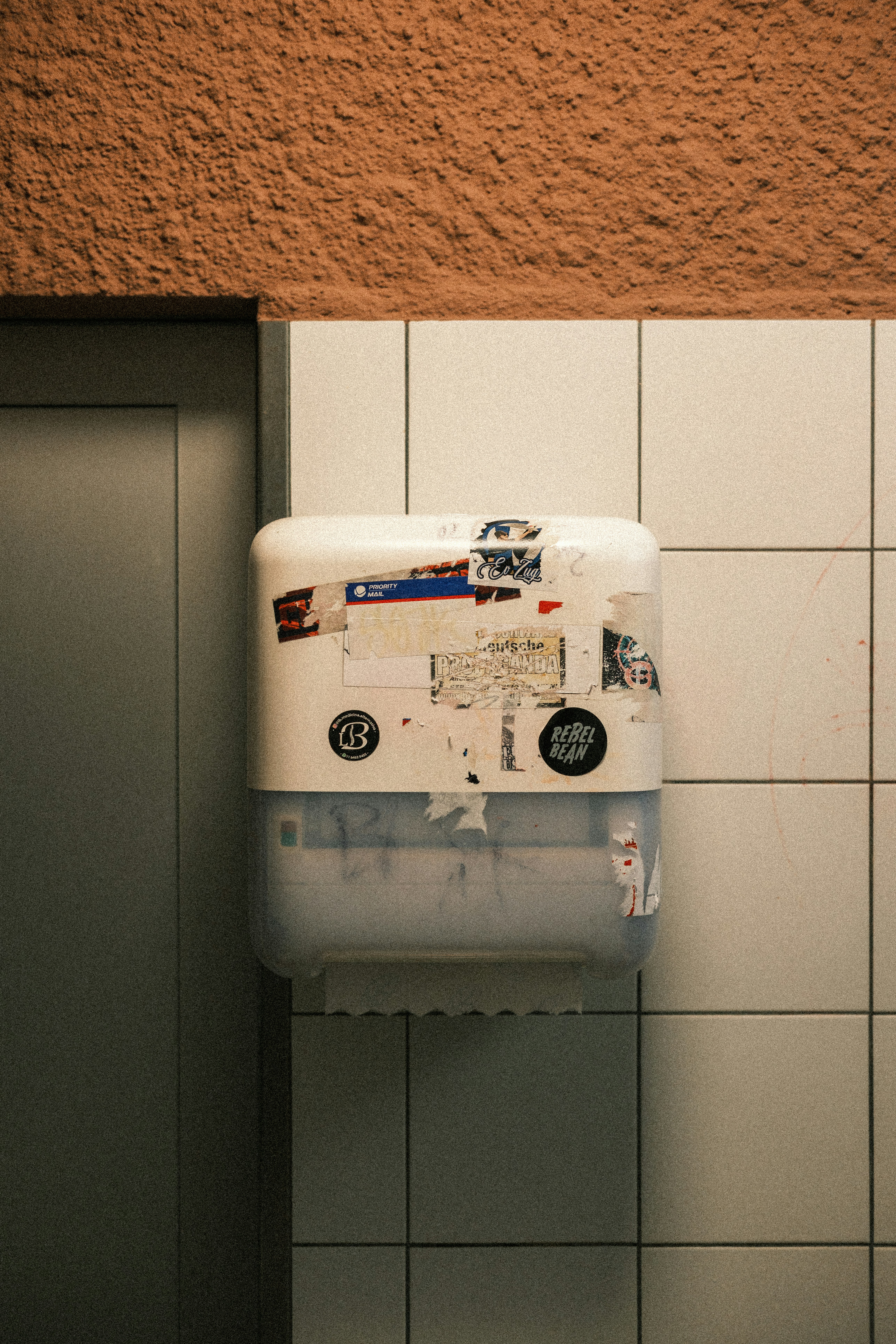 A Weathered Mailbox Anchored to Tiled Wall in Suburban Hallway