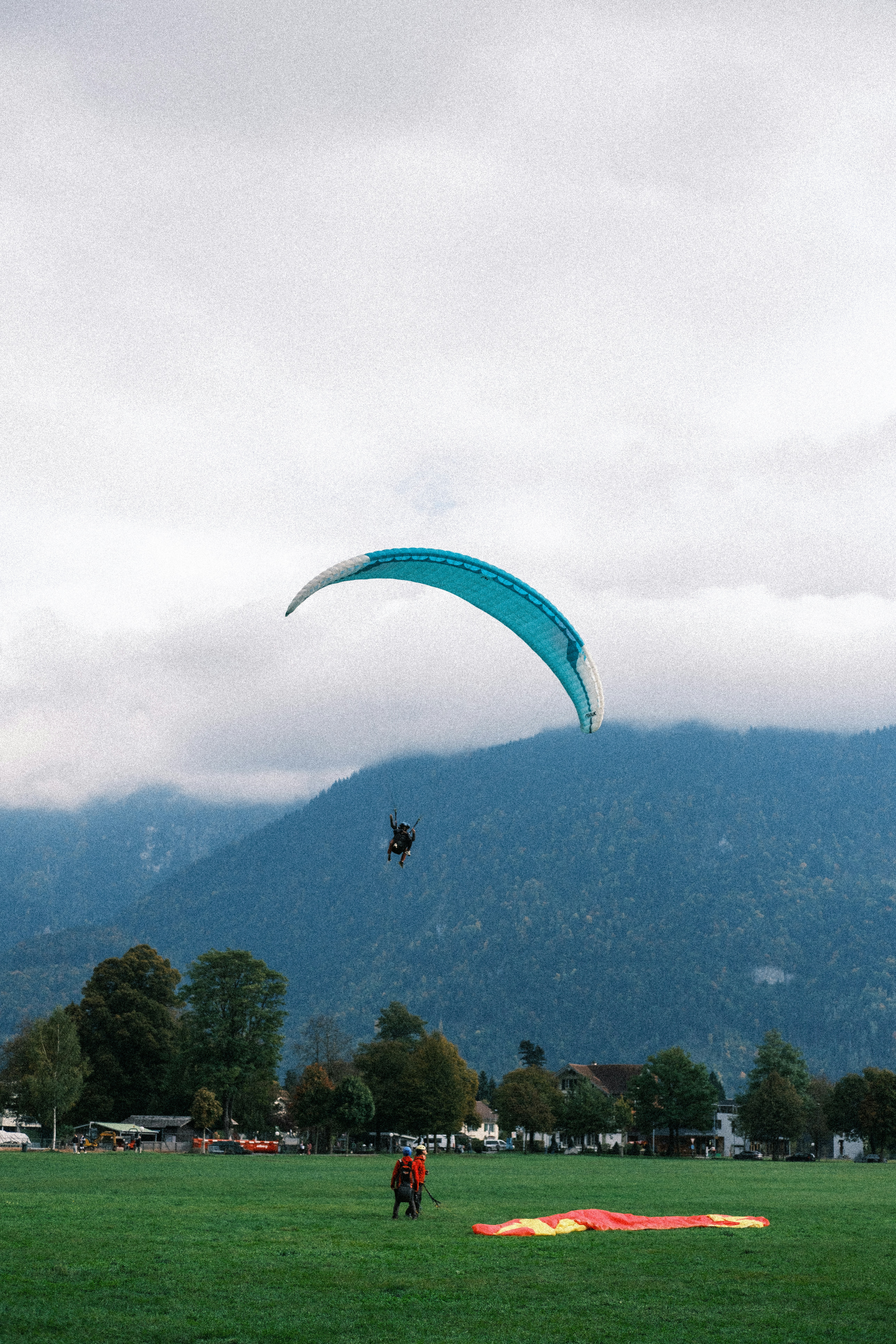 Blue paraglider over a grassy field with distant hills